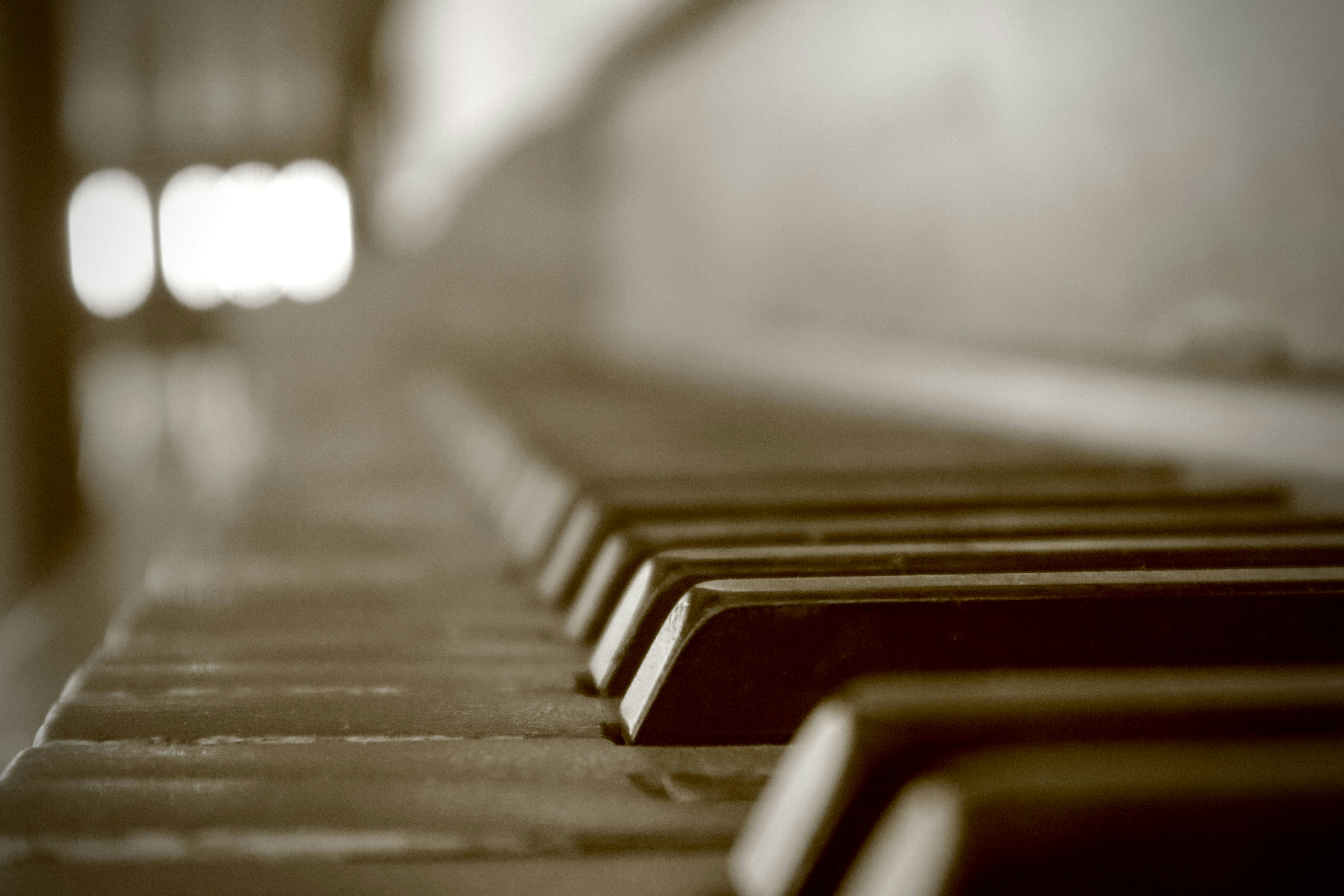 Sepia-toned image of piano keys with shallow depth of field, drawing focus toward the mid-to-front area of the keyboard; the scene emphasizes texture and mood rather than sharp detail. This is a photography capture of a piano environment.