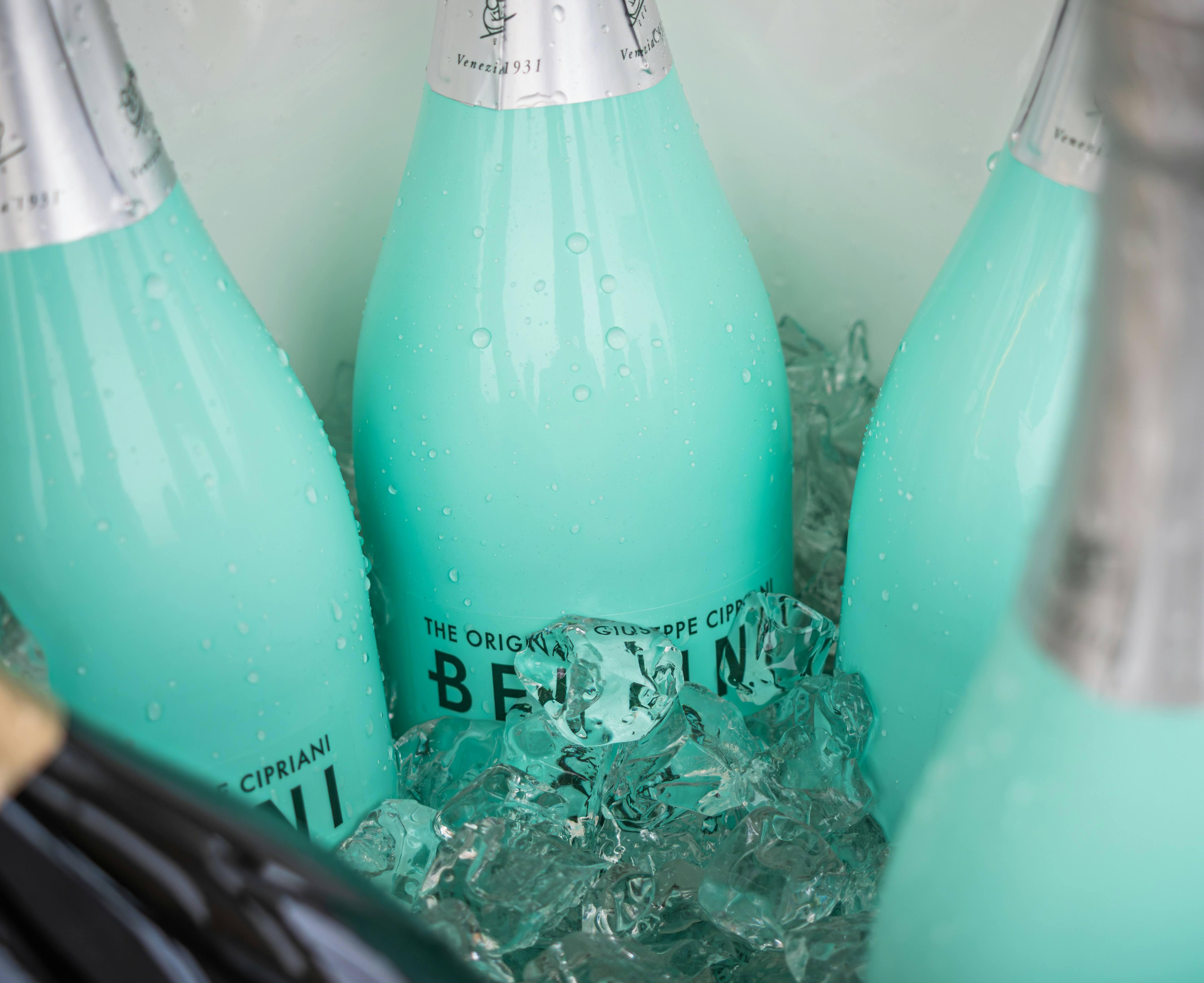 Turquoise bottles of bellini sparkling wine chilling in ice.