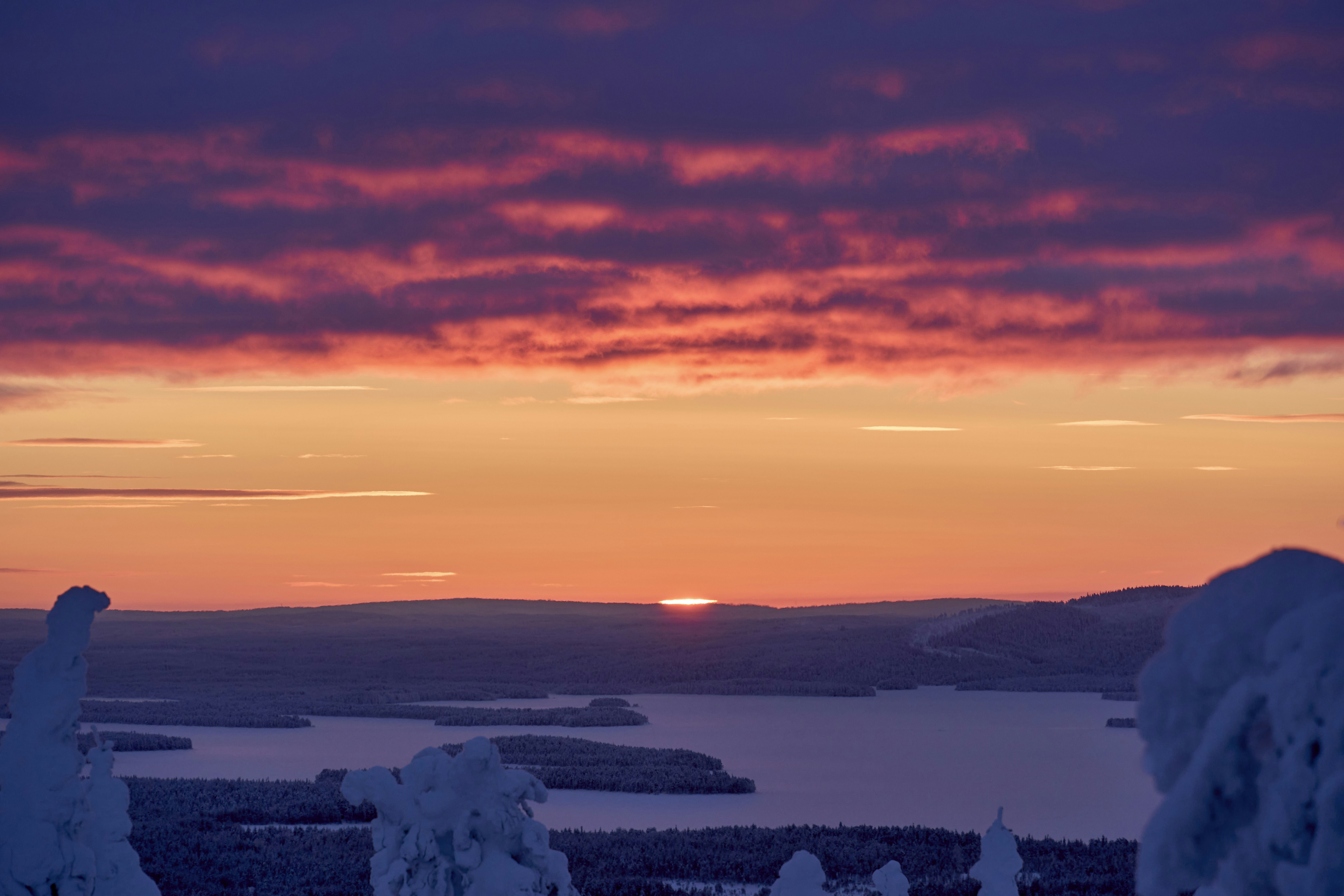 Dusk Over Frosted Horizon: A Tranquil Sunset from a Snow-Covered Outcrop