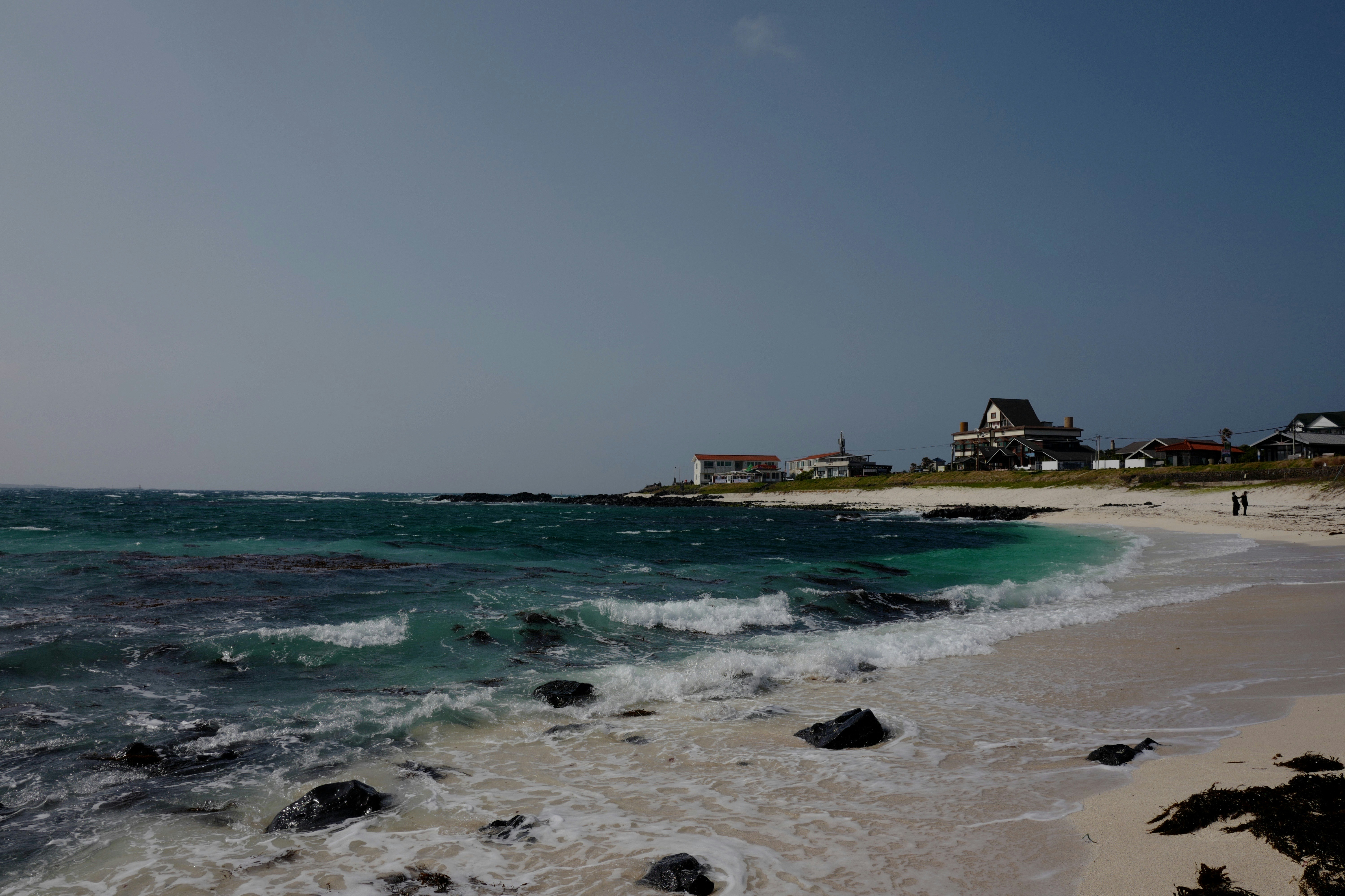 Coastal Village Edge: Waves Break Against a Quiet Shore