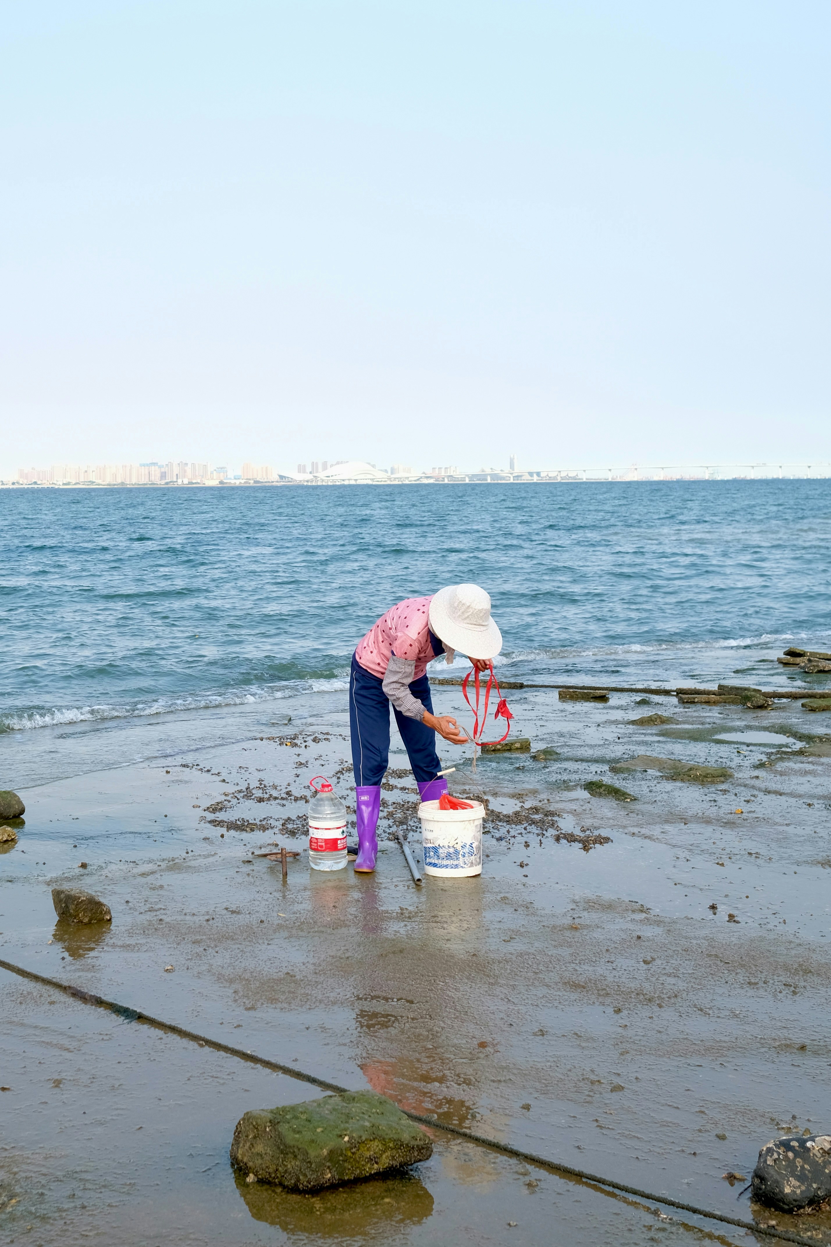 Beach Gardener in a Pink Shirt Tends to Tide-Washed Buckets