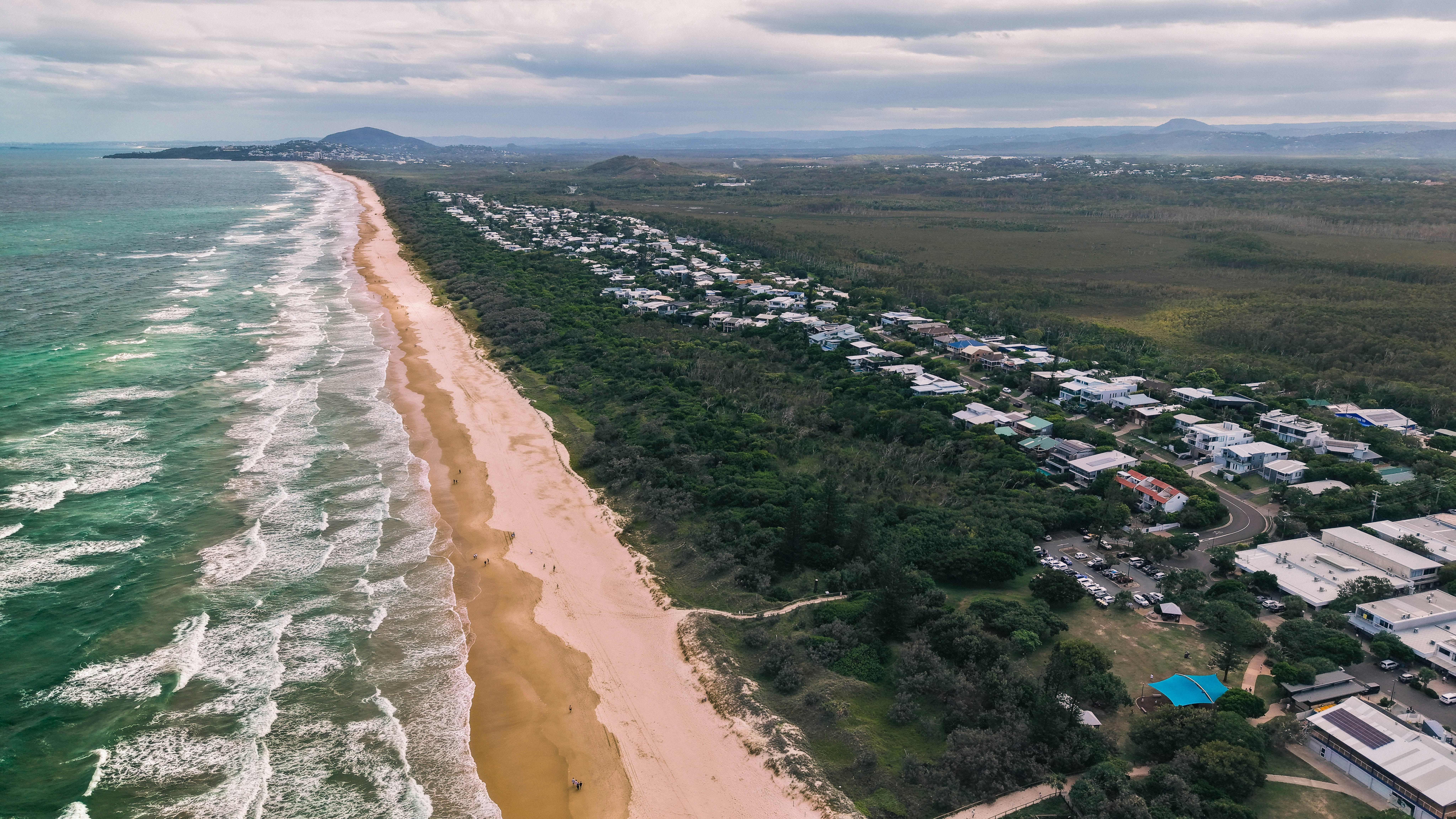 Coastal town with long sandy beach and ocean waves.