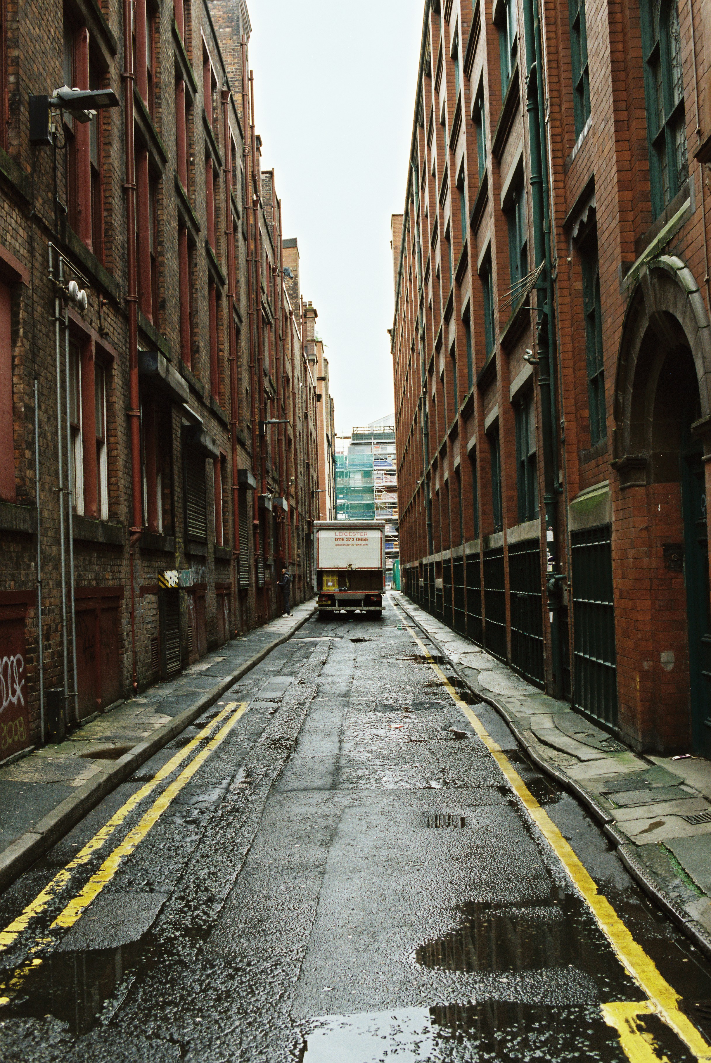 Lane of Wet Echoes: A Truck Recedes Through a Narrow Brick Gorge