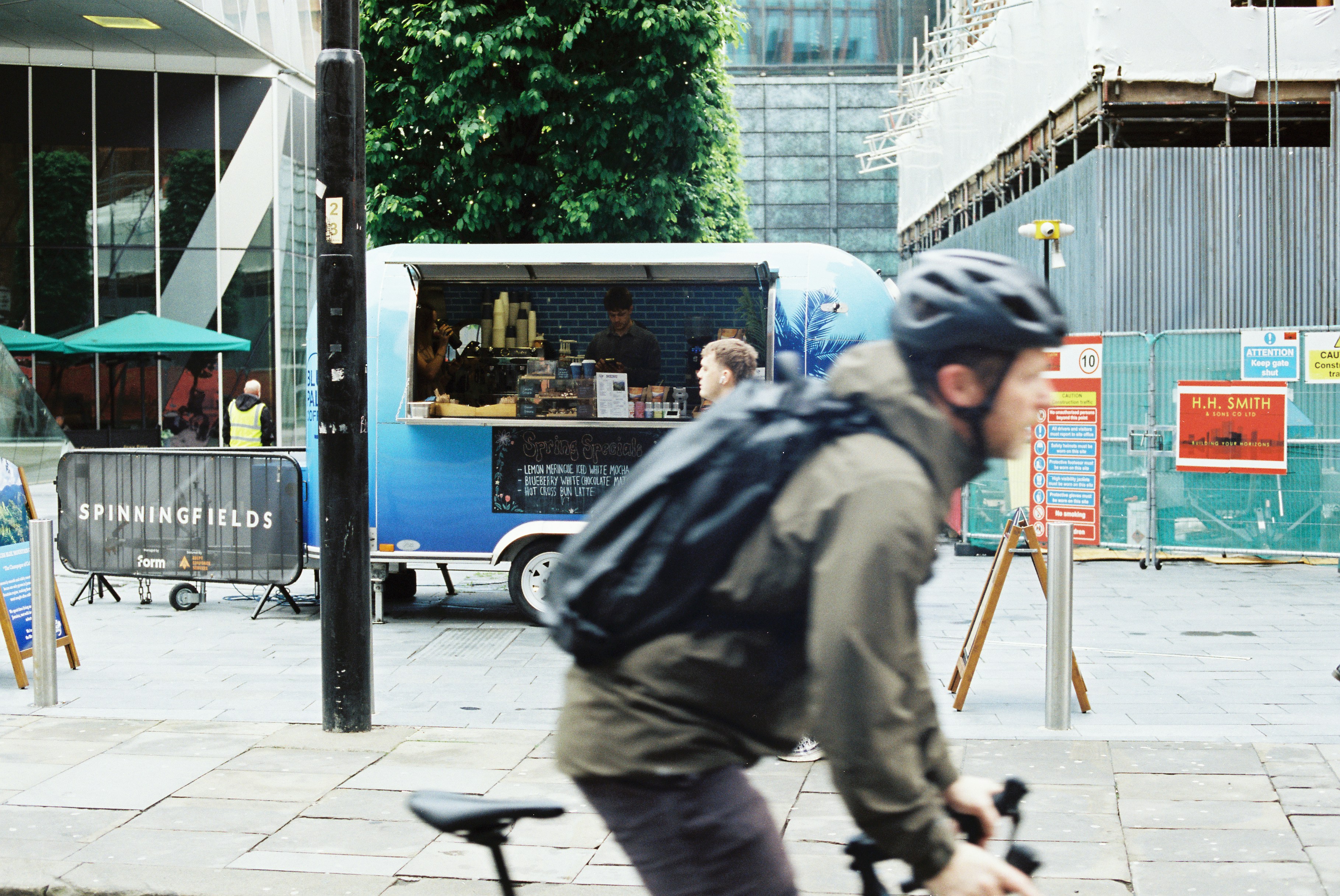 Cyclist in motion past a blue food truck amid urban construction