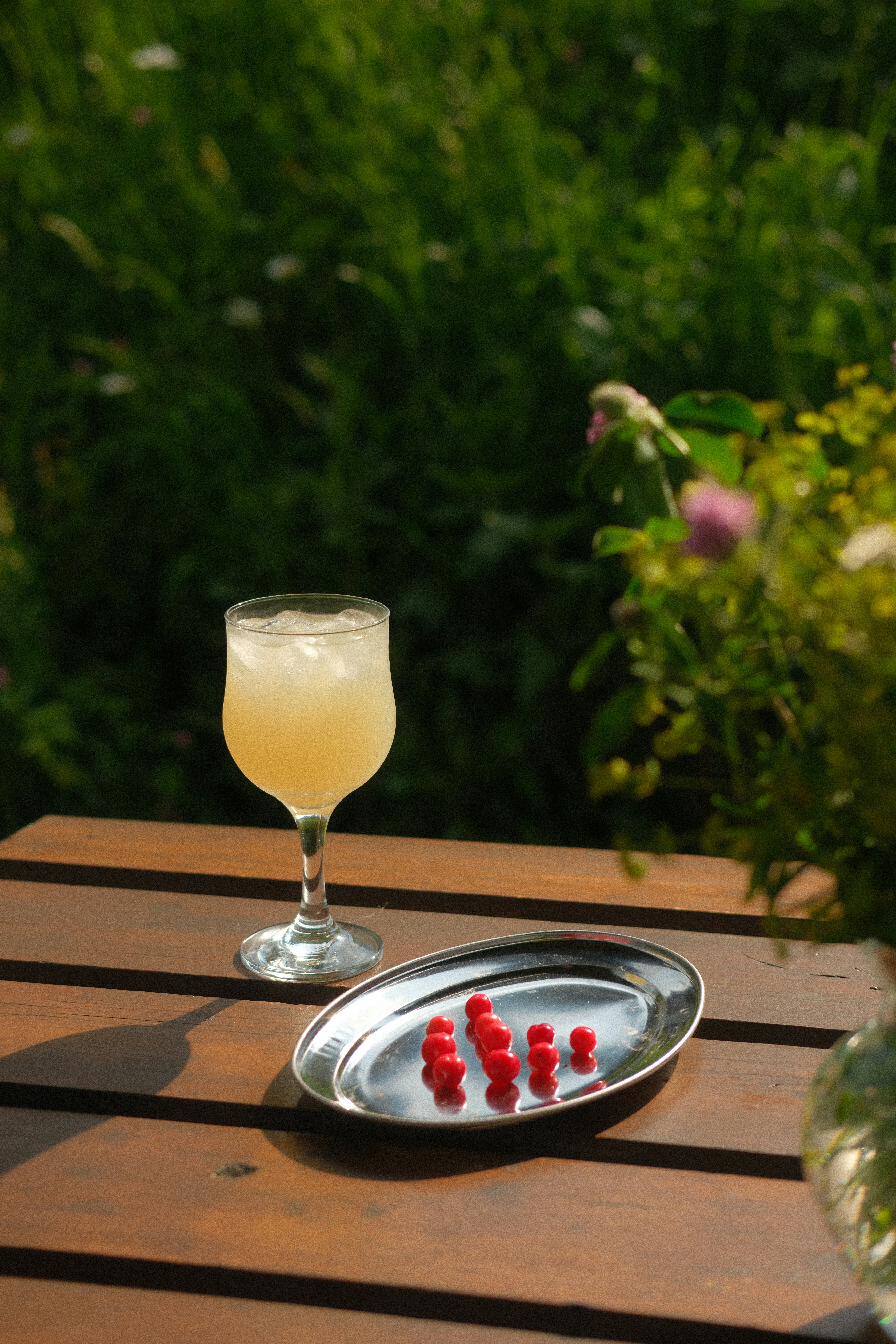 Drafts on a Sunlit Terrace: A Glass of Citrus Amid Red Berries