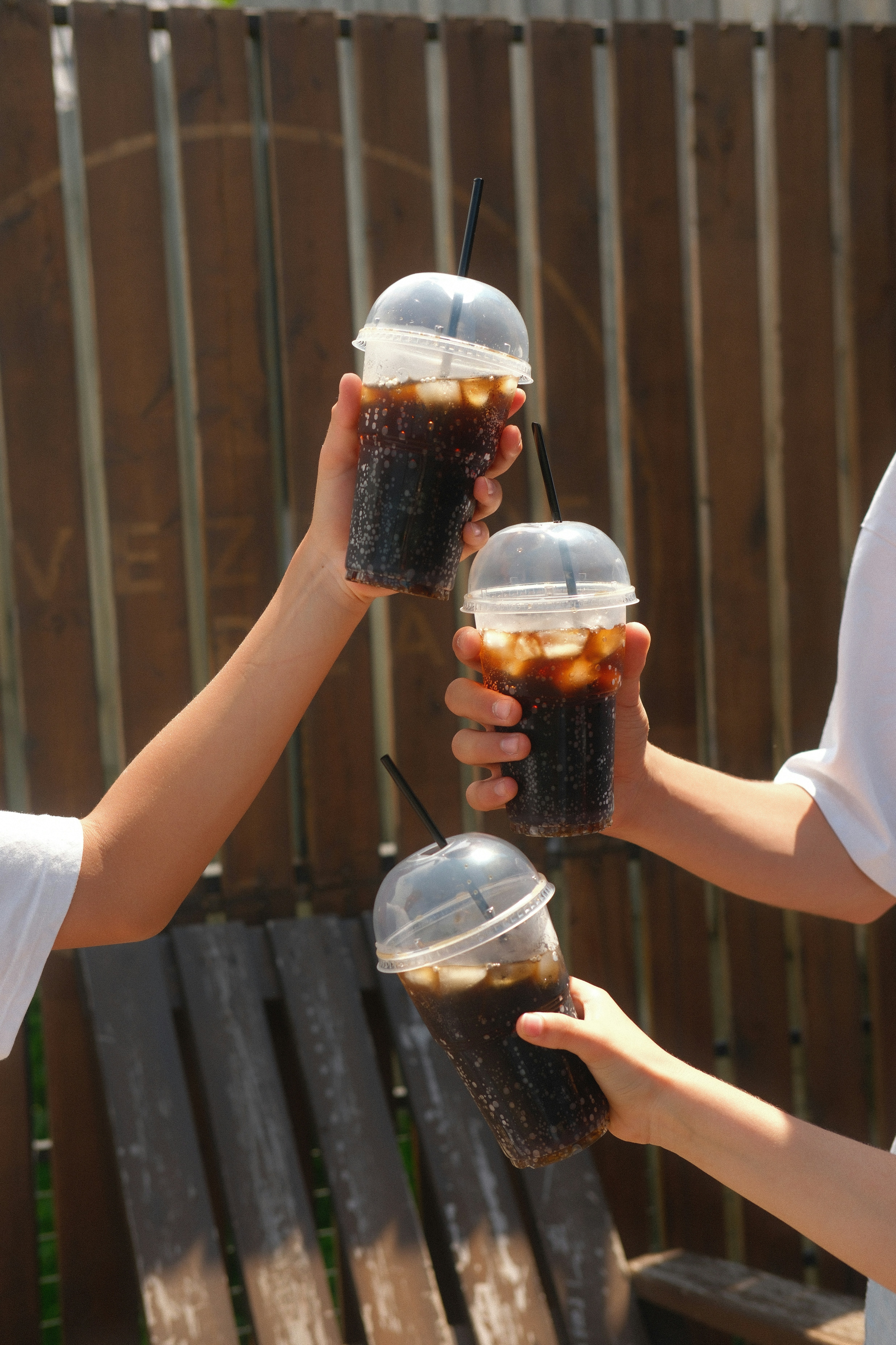 Toasts in Motion: Clinking Iced Cocoa Cups Across a Fenced Patio