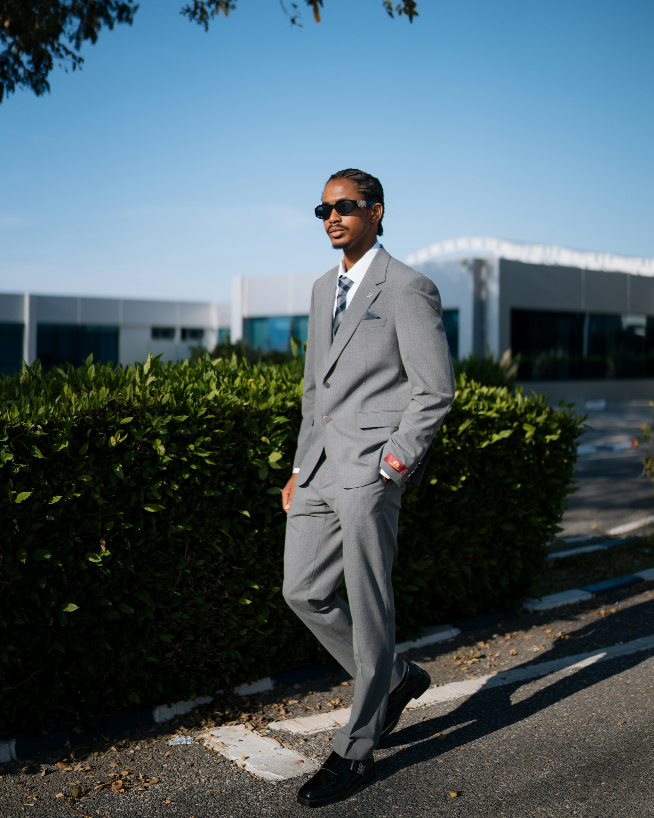 Sharp-suited silhouette: a poised executive strides past hedges