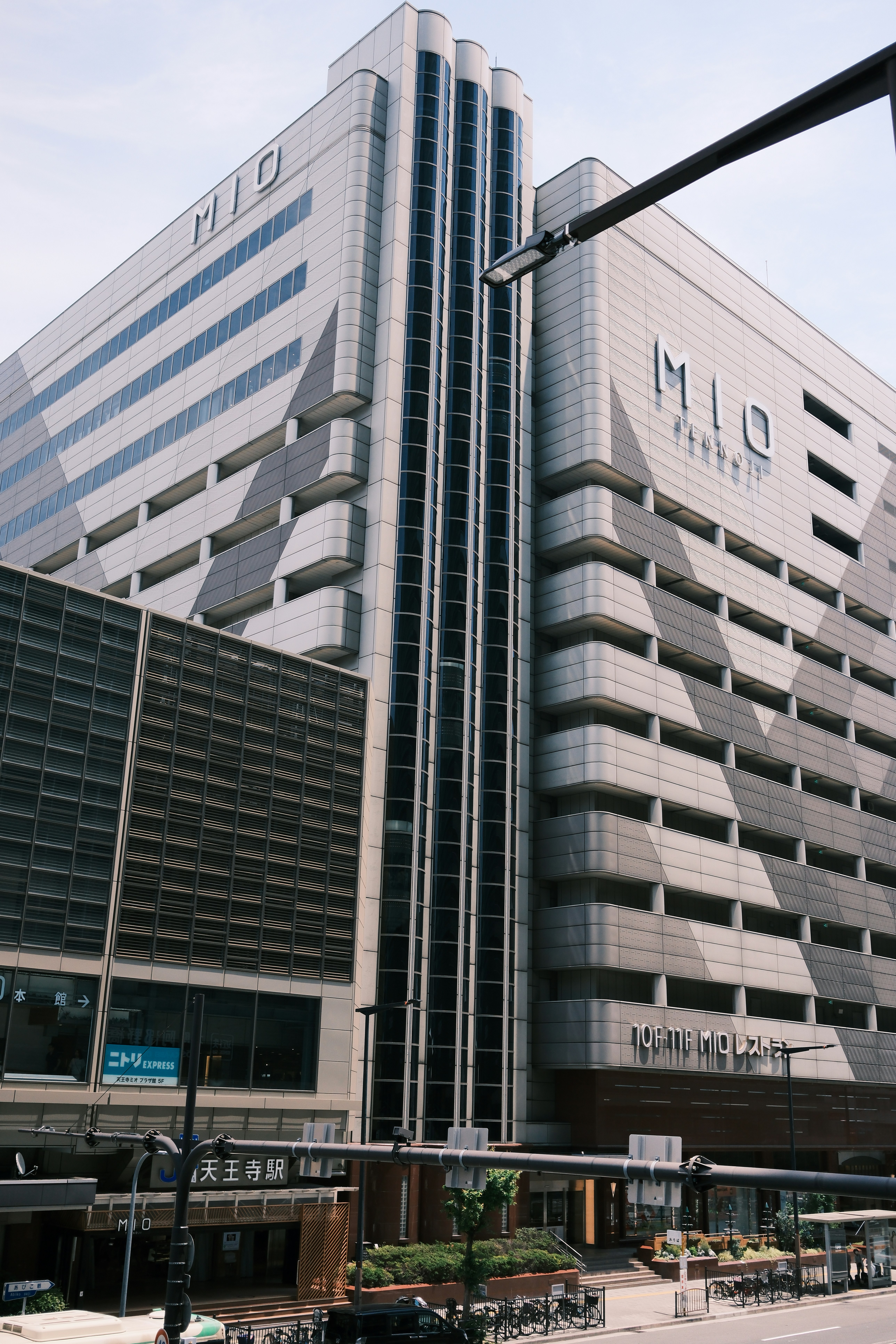Modern urban building with "mio" sign and geometric patterns.