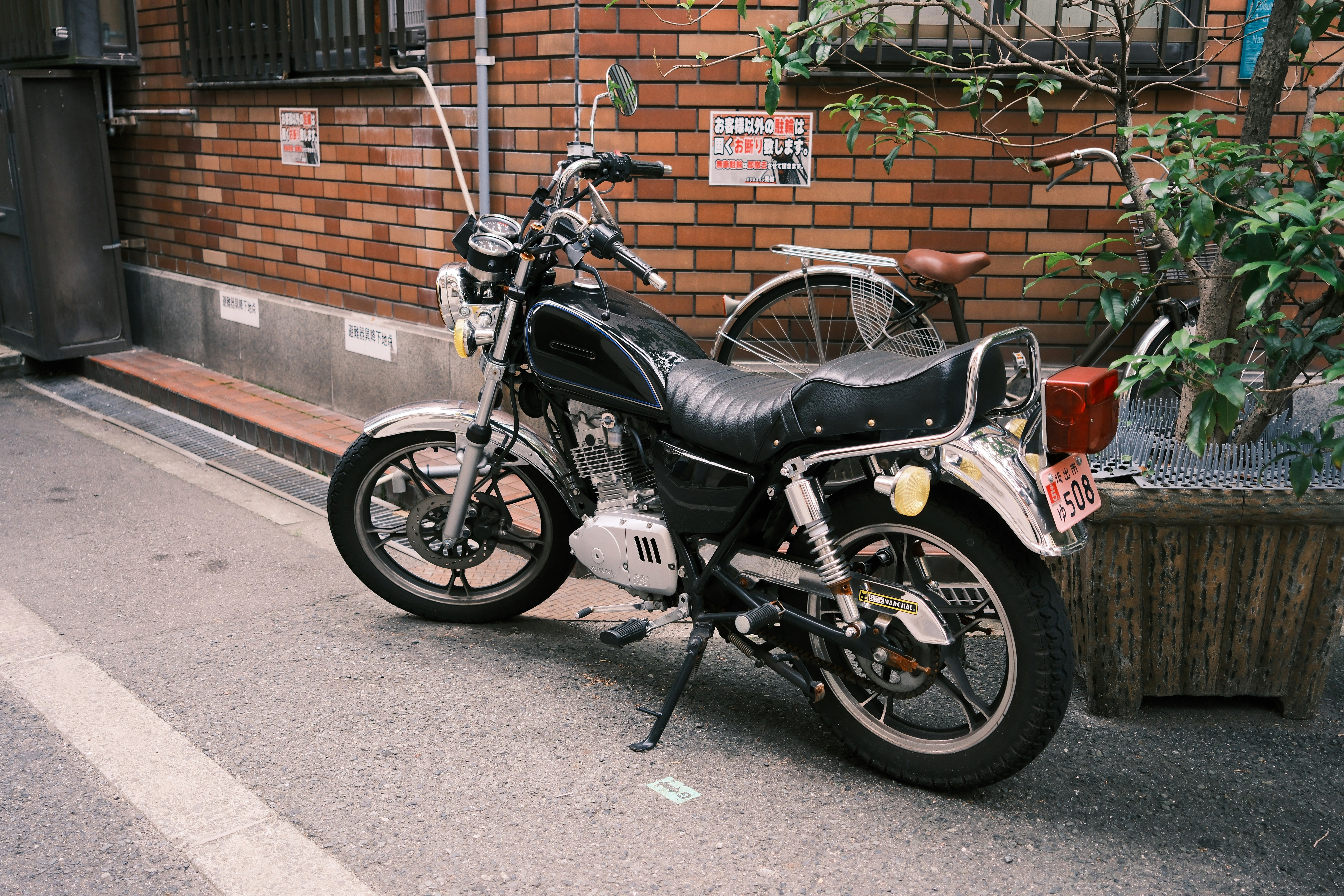 Midnight Riser: A Classic Motorcycle Resting by a Brick Wall