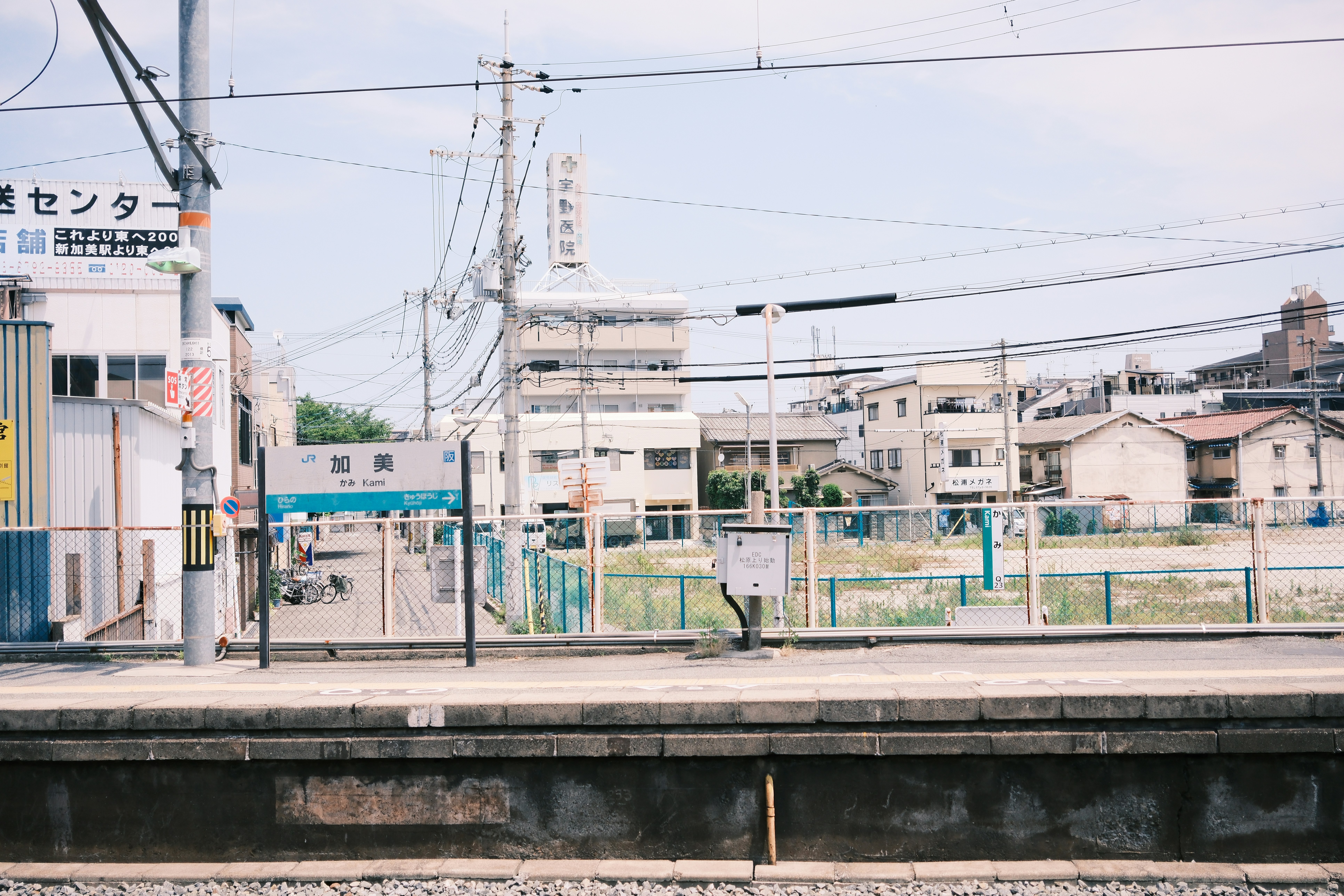 A train station platform with buildings and power lines.
