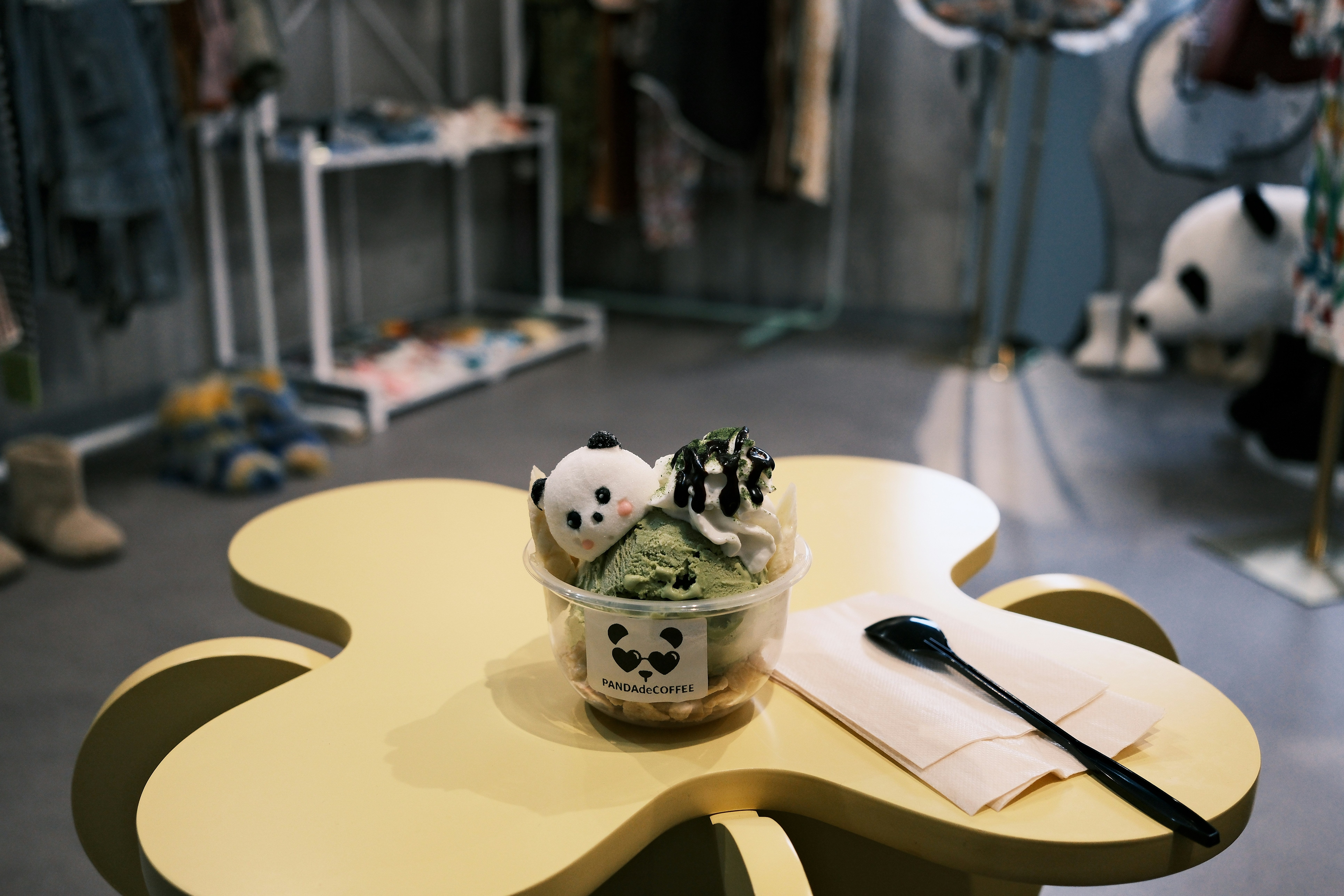 Green ice cream with panda toppings on a yellow table.