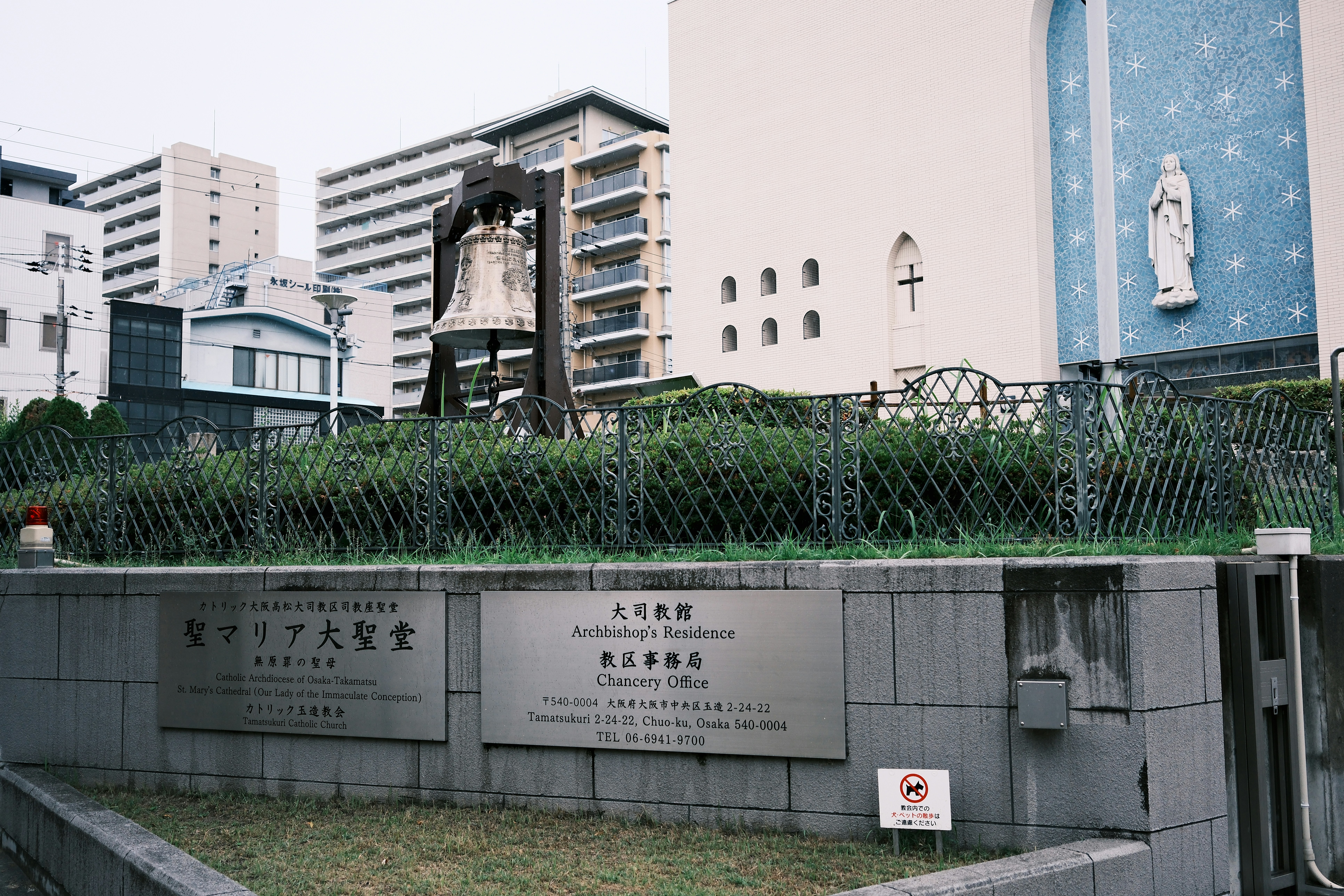Bell Tower and Blessings: A Quiet Church Courtyard Amid Urban Elevation