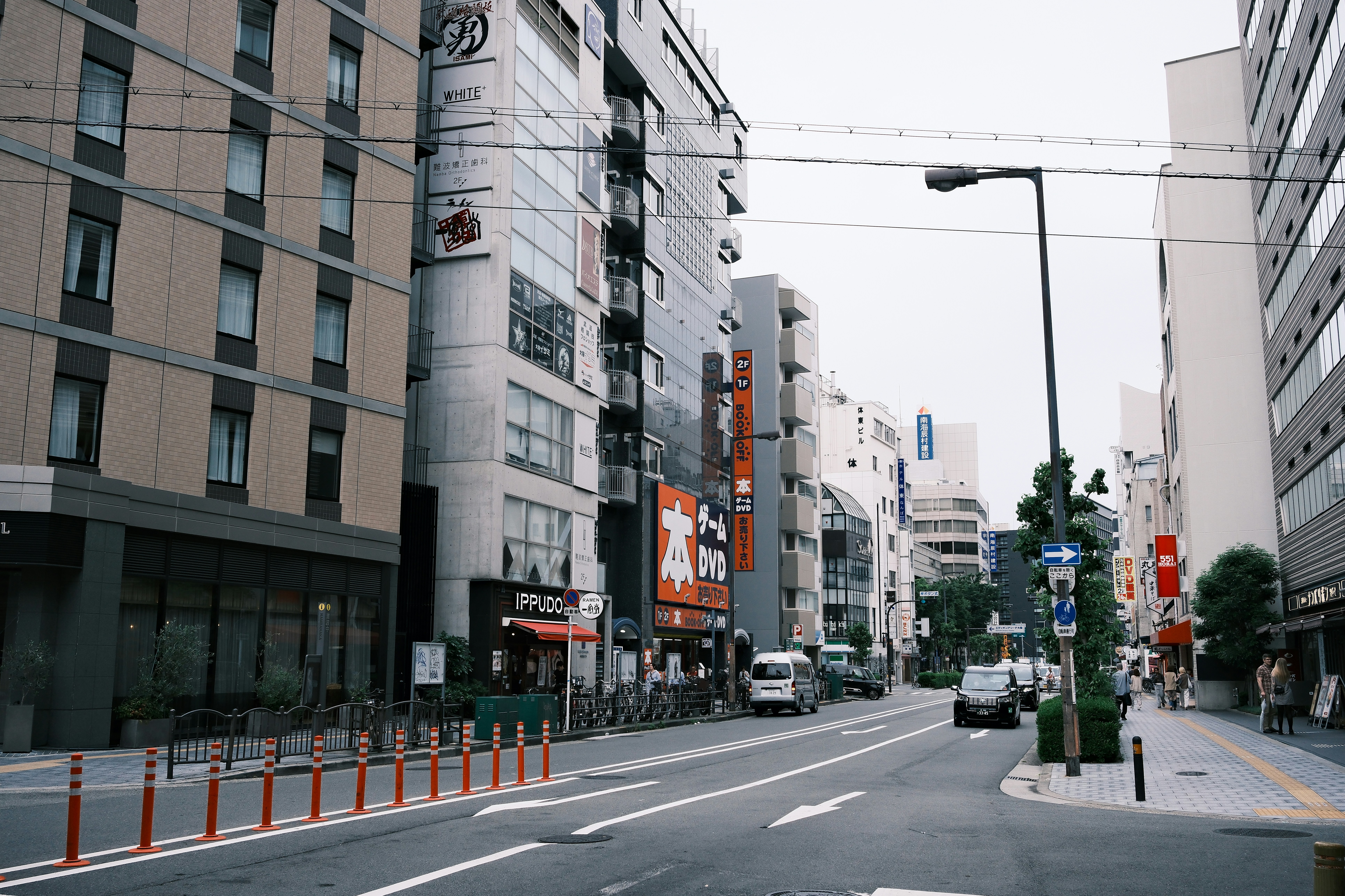 Urban street lined with buildings, cars, and people.