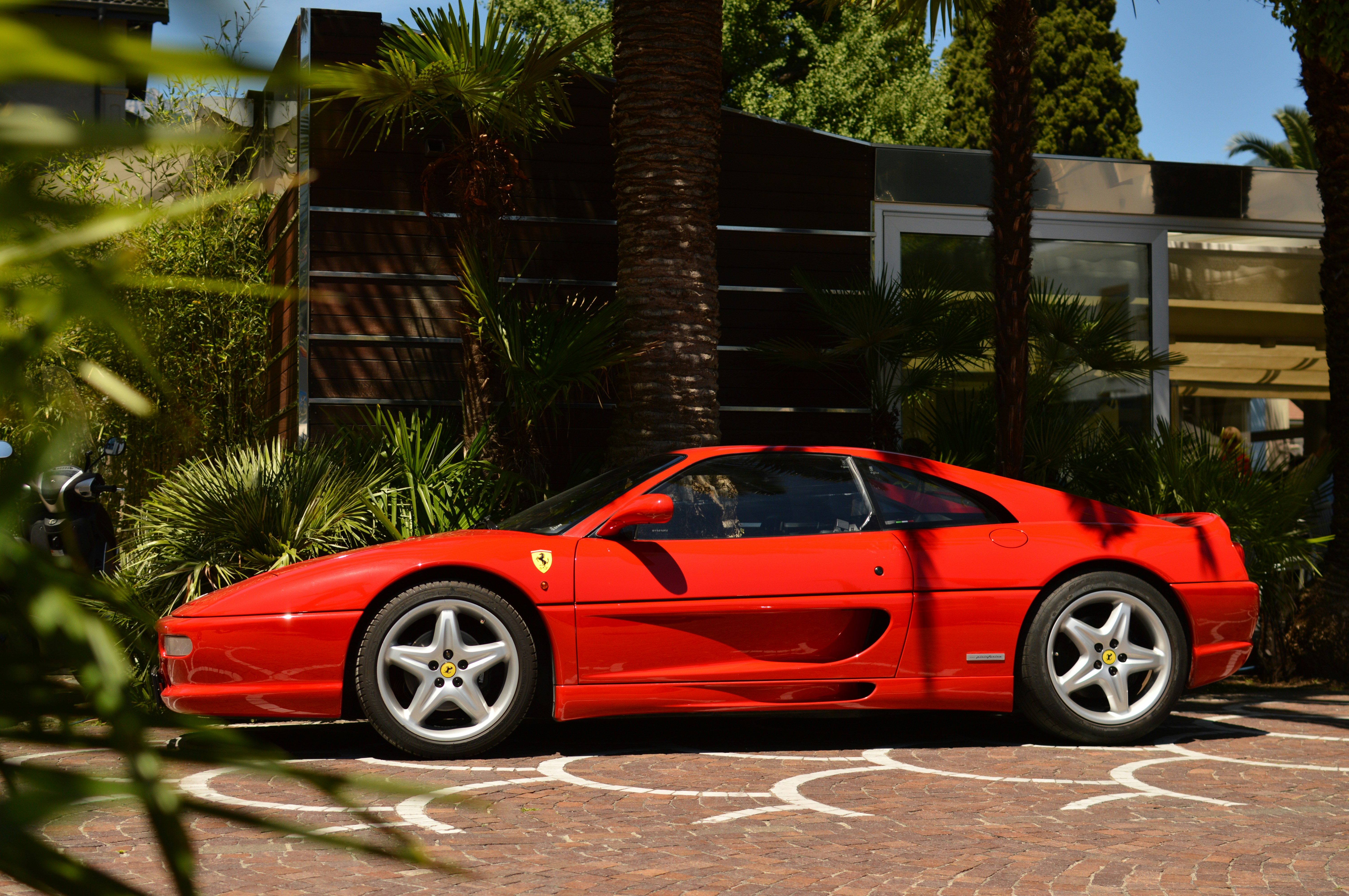 Red Prancing Rosso: a Ferrari F355 parked amid tropical greens