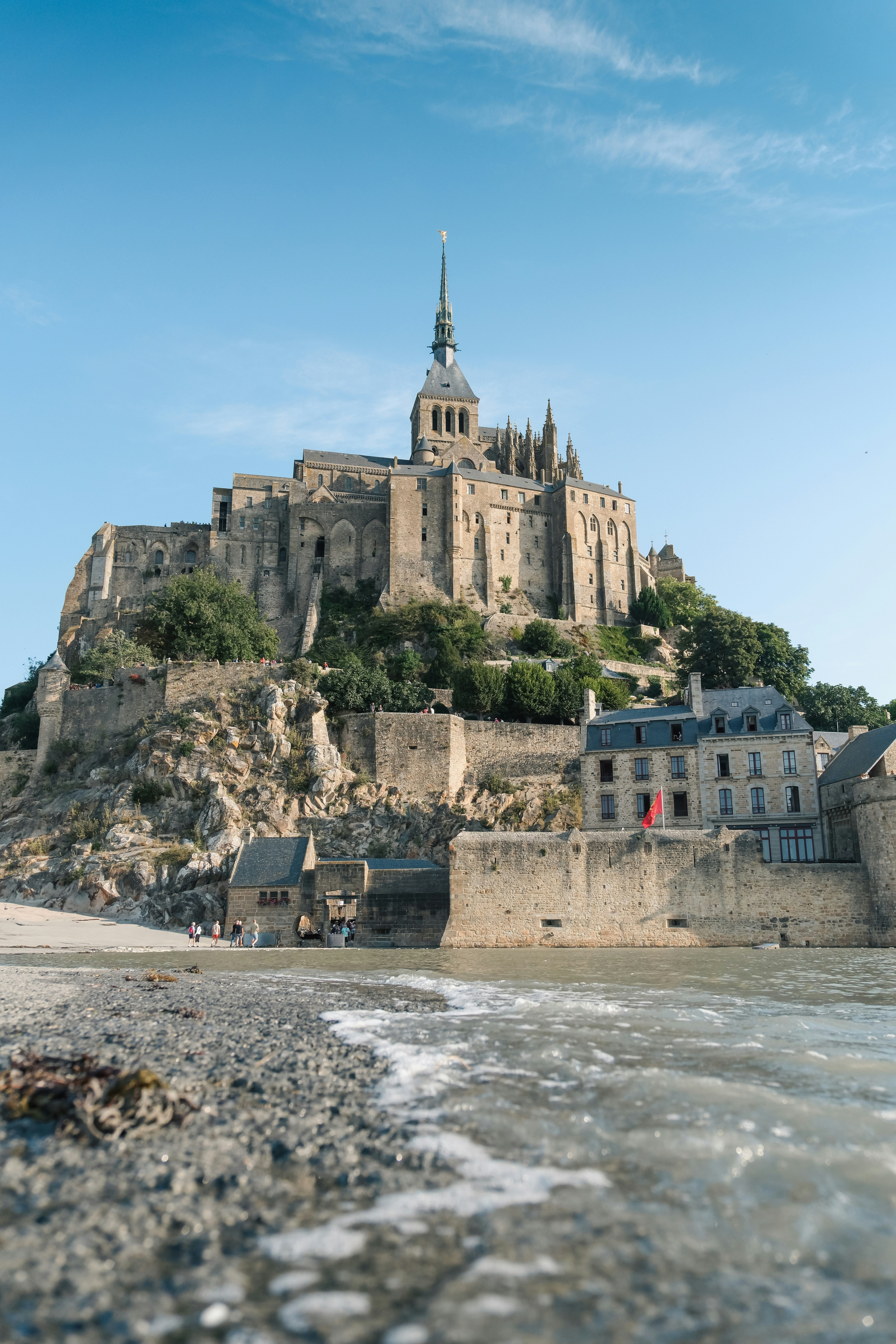 Mont Saint-Michel rising above a rocky coast under a clear afternoon sky