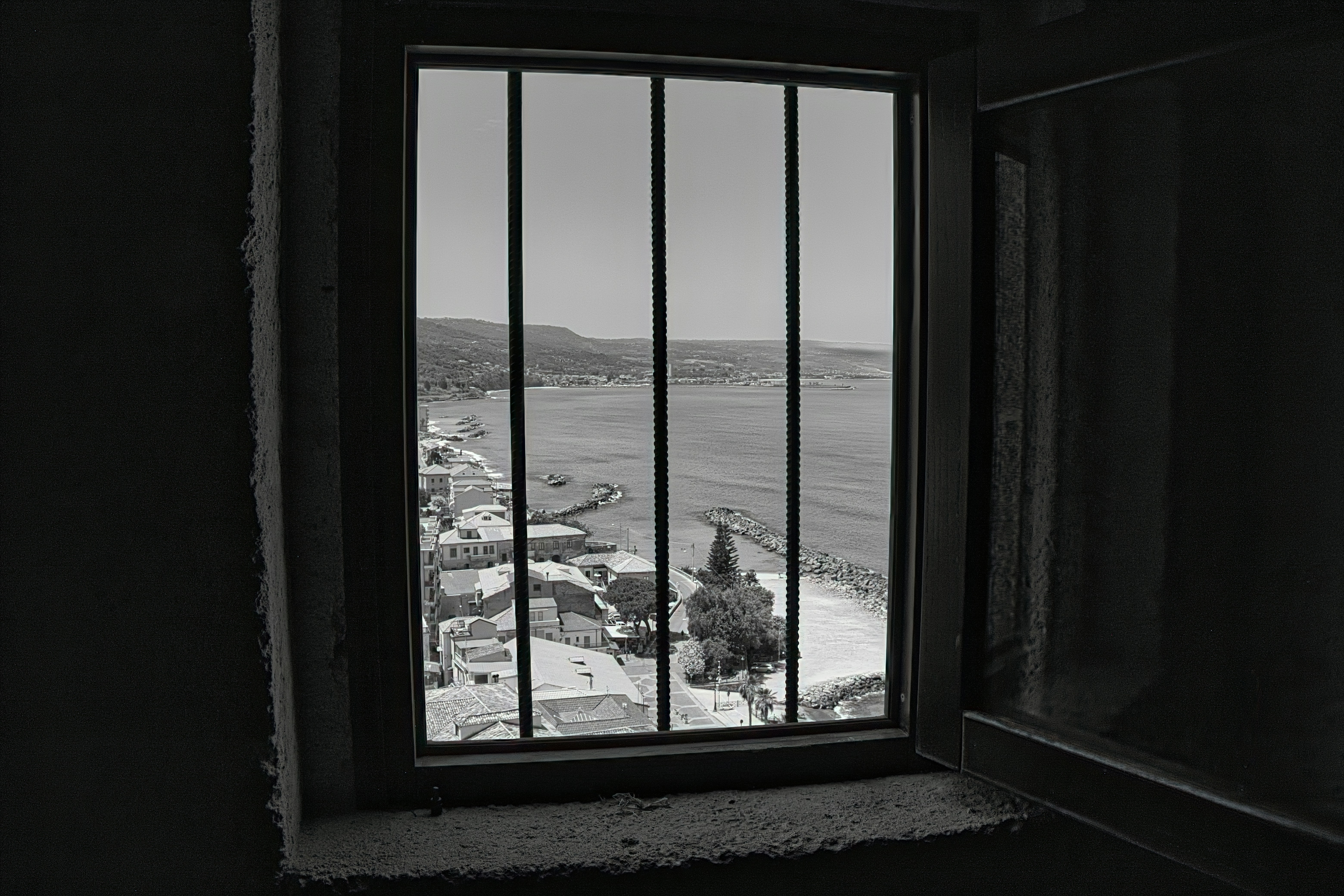 View Through the Rustic Window: Seaside Town Beyond Bars