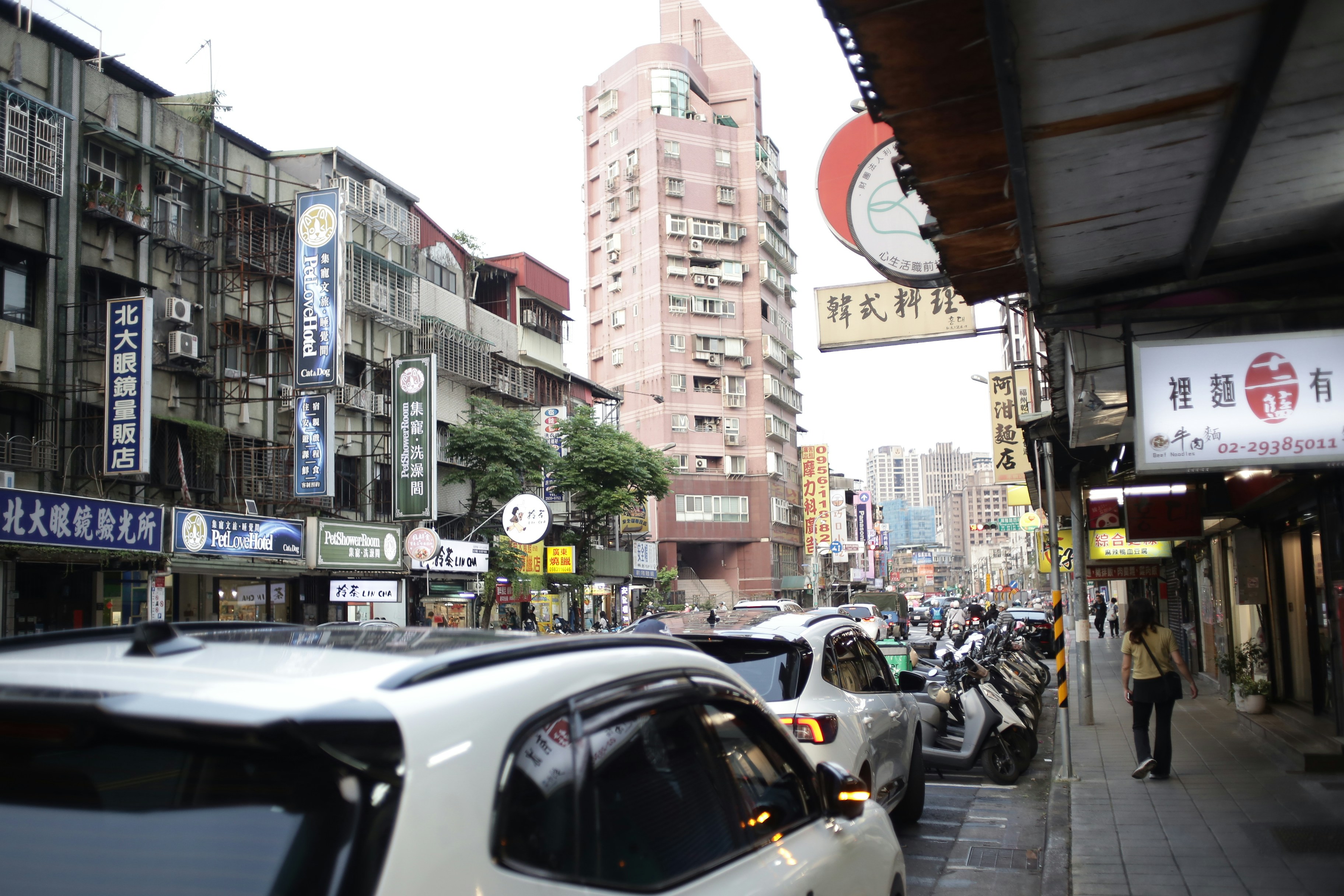 City Street Chorus: Cars, Shops, and Signs in a Bustling Asian Corridor