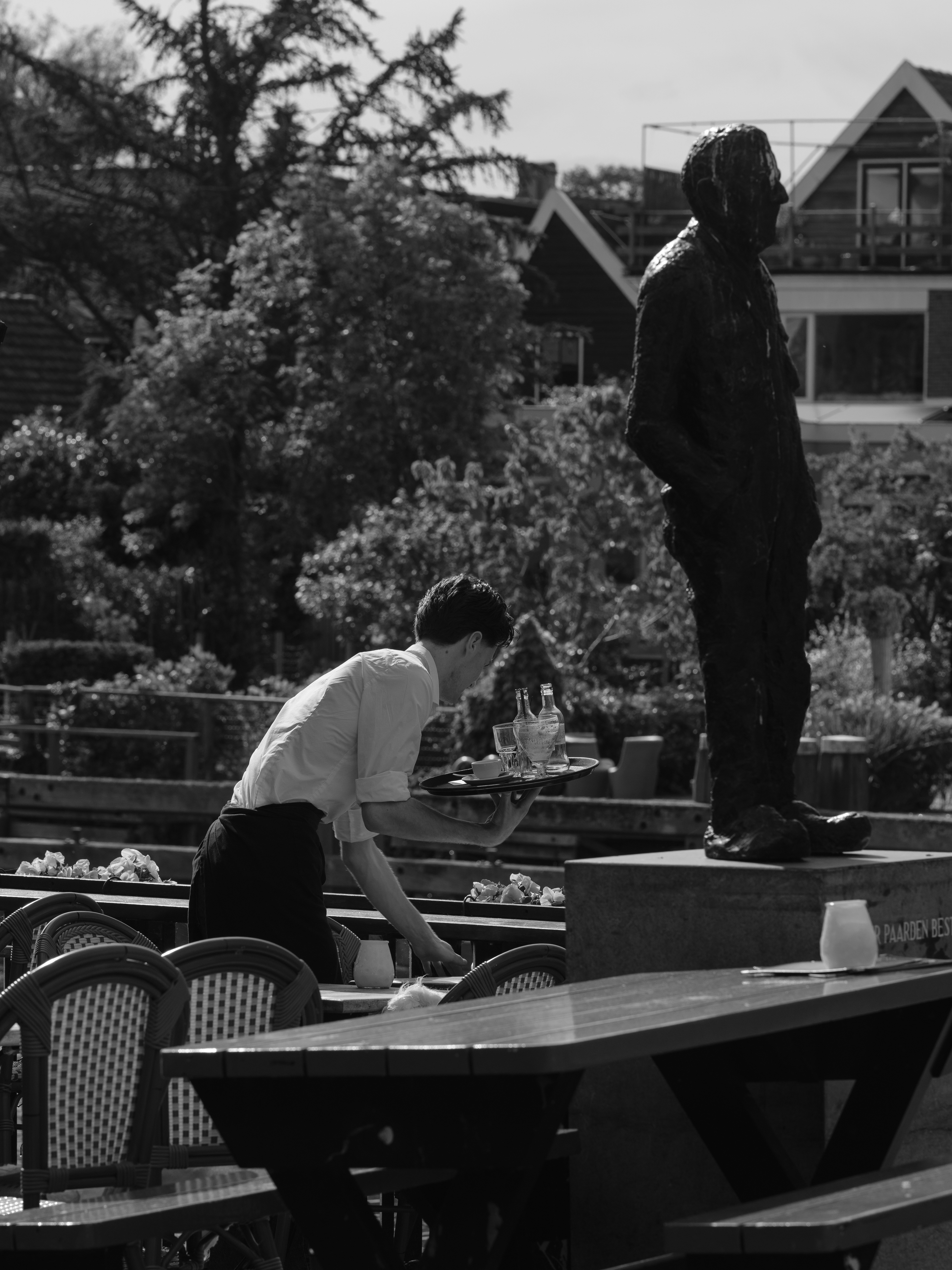 The Silent Service: A Waitstaff Balance Behind a Statue