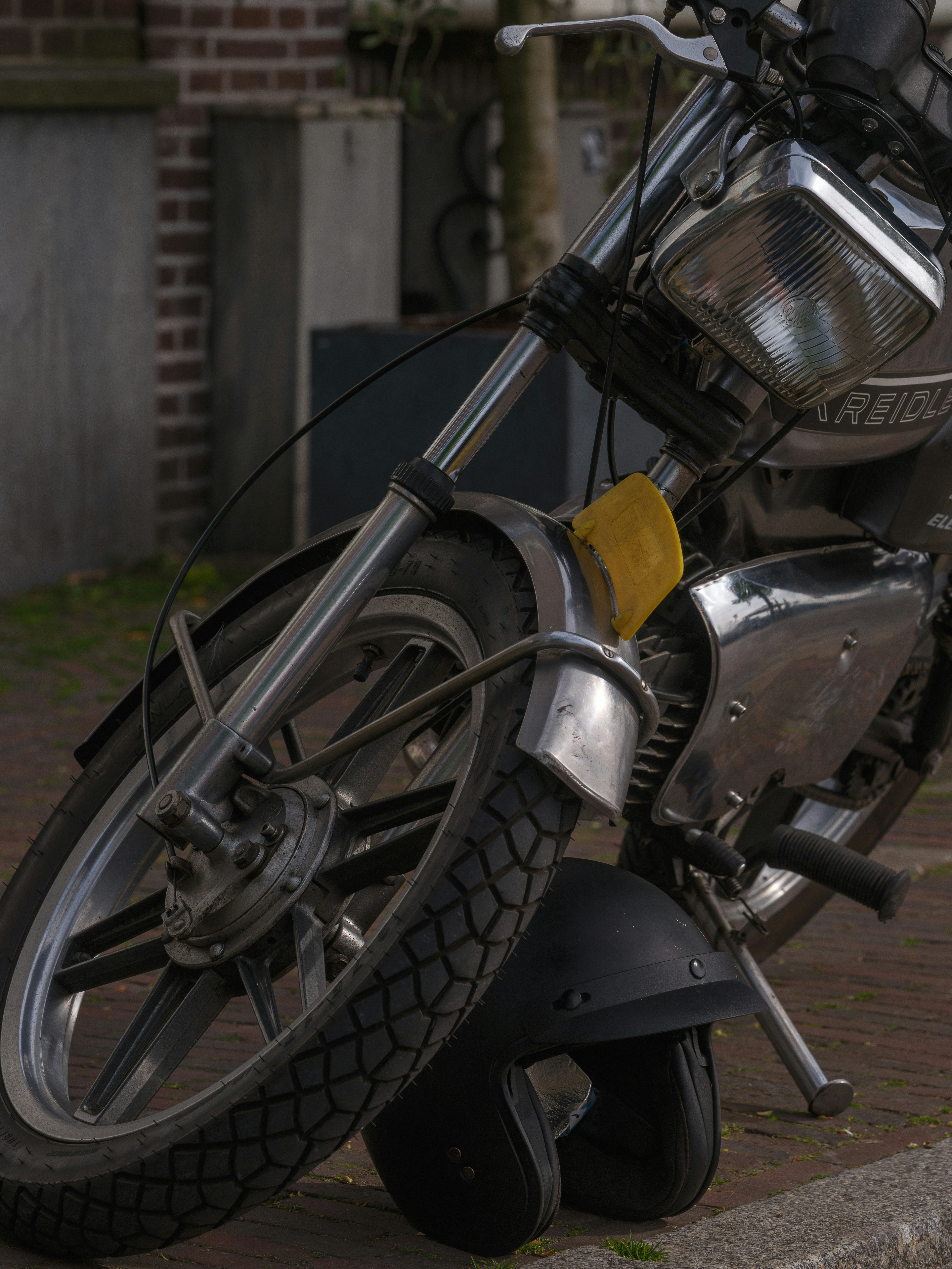 Close-up of a vintage-styled motorcycle resting on a brick path