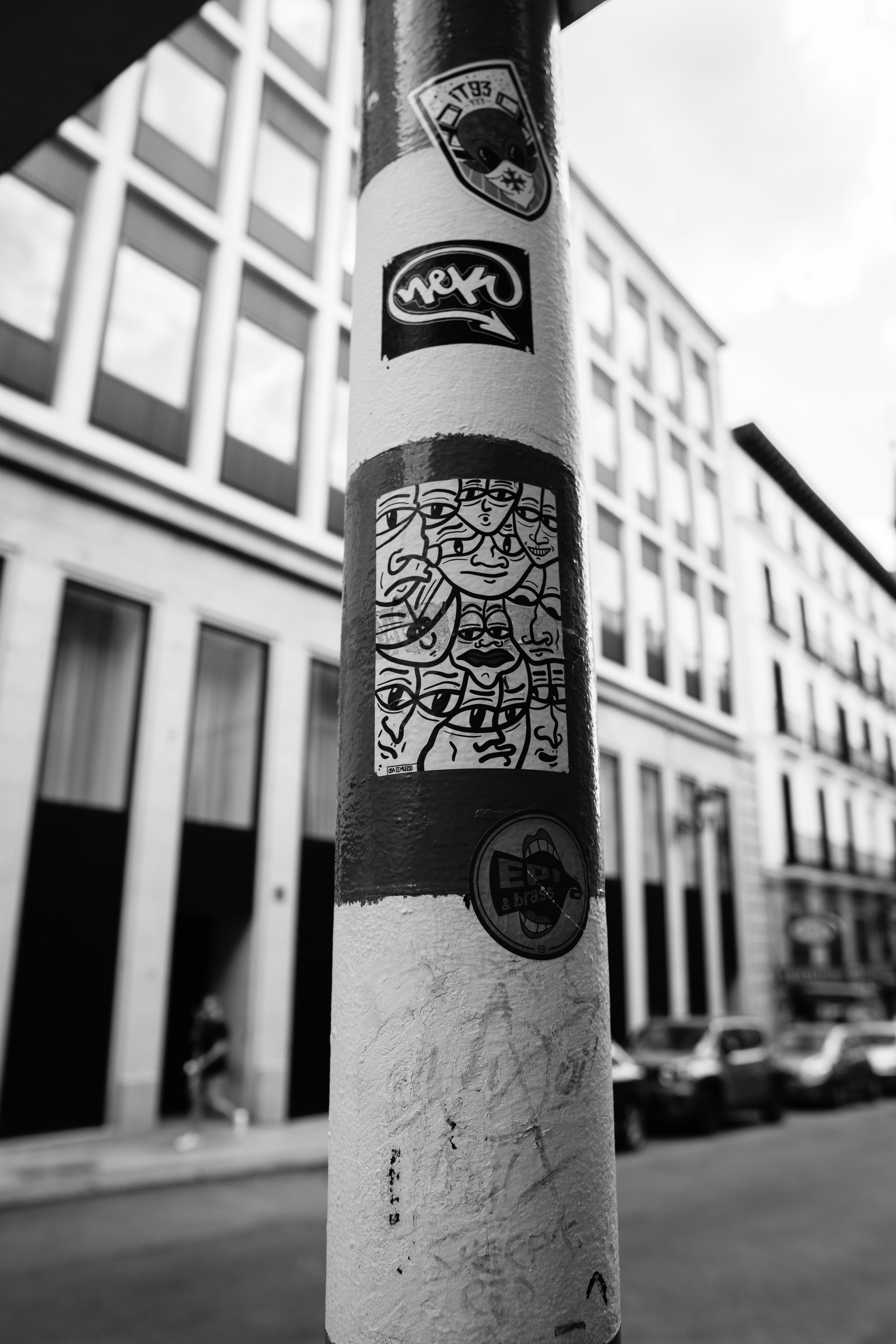 Urban Stickered Pole: A Vertical Portrait of Street Art and Concrete Facades