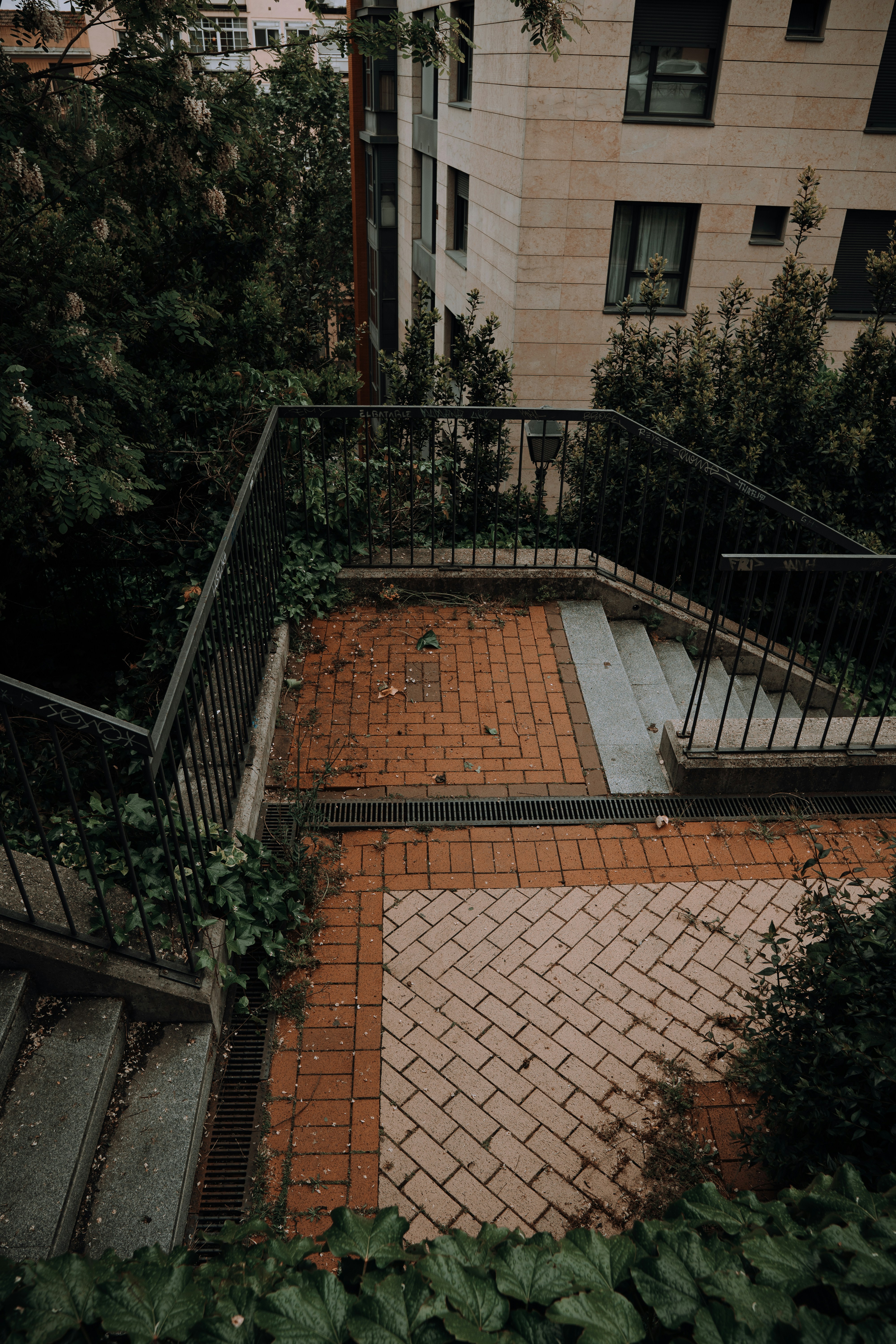 Terraced descent: urban courtyard stairs framed by brick and greenery