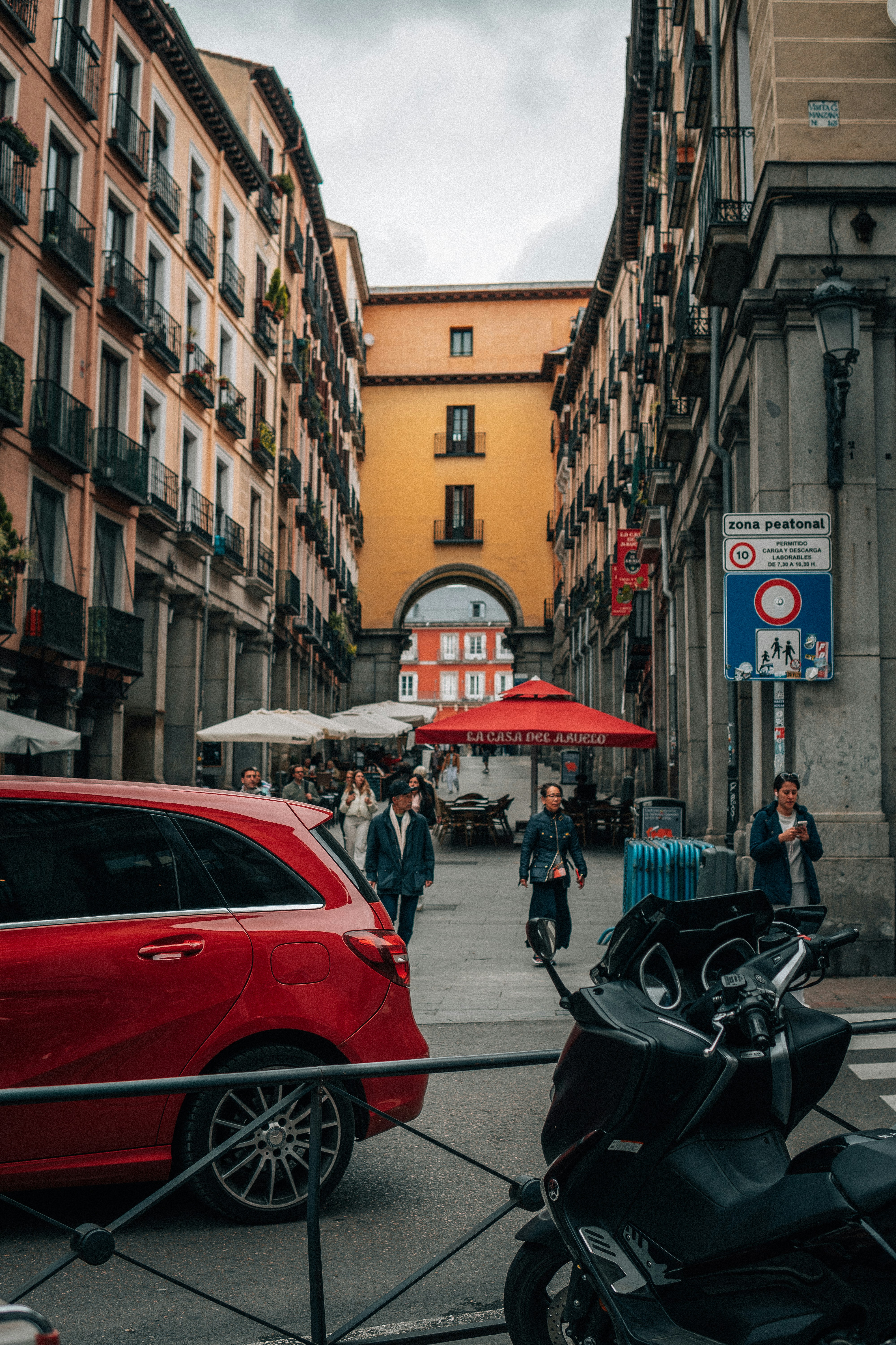 Arched Alleyway Café Amid Red Car and Scooter Rumble