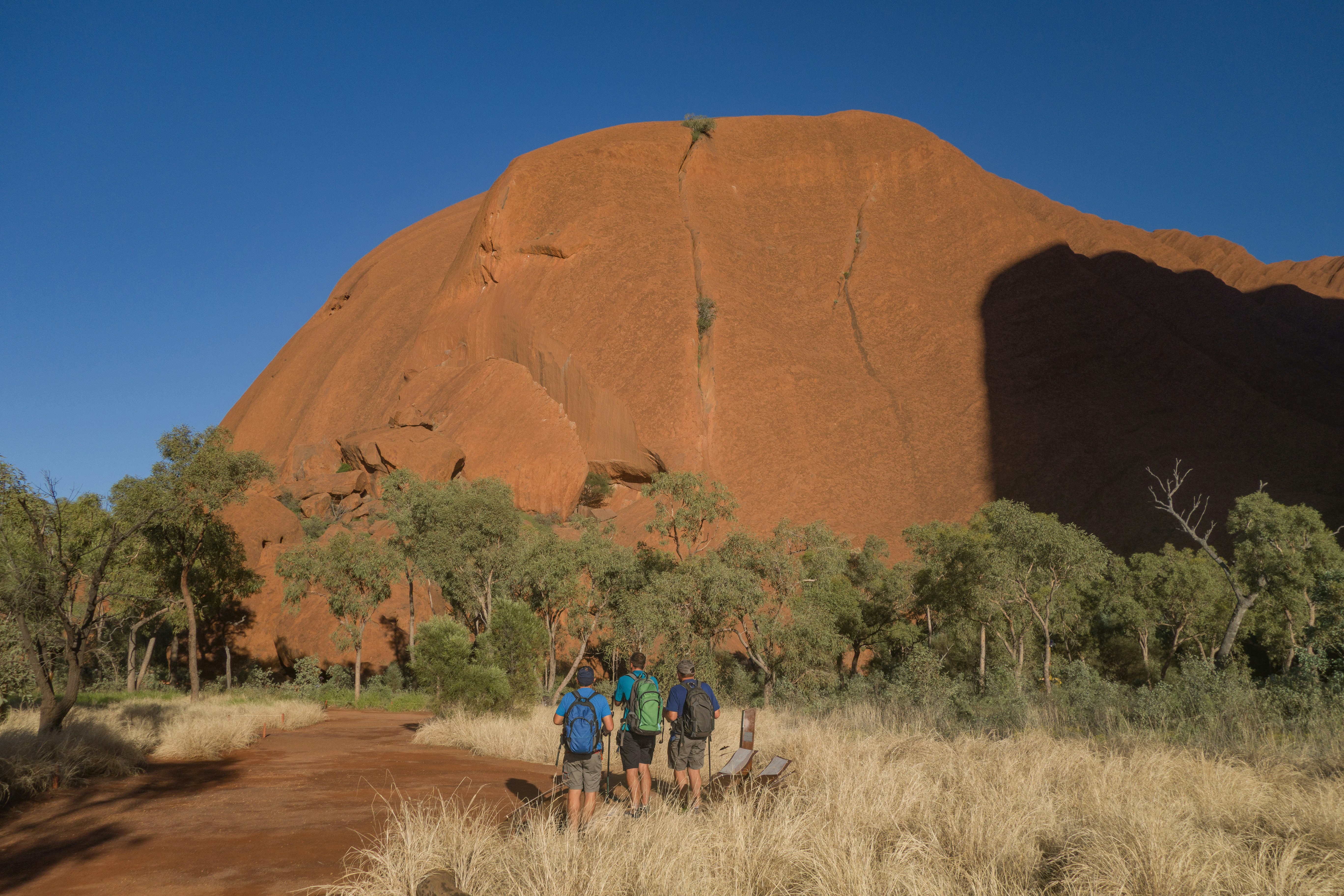 Hikers at the Base of a Monolithic Red Rock
