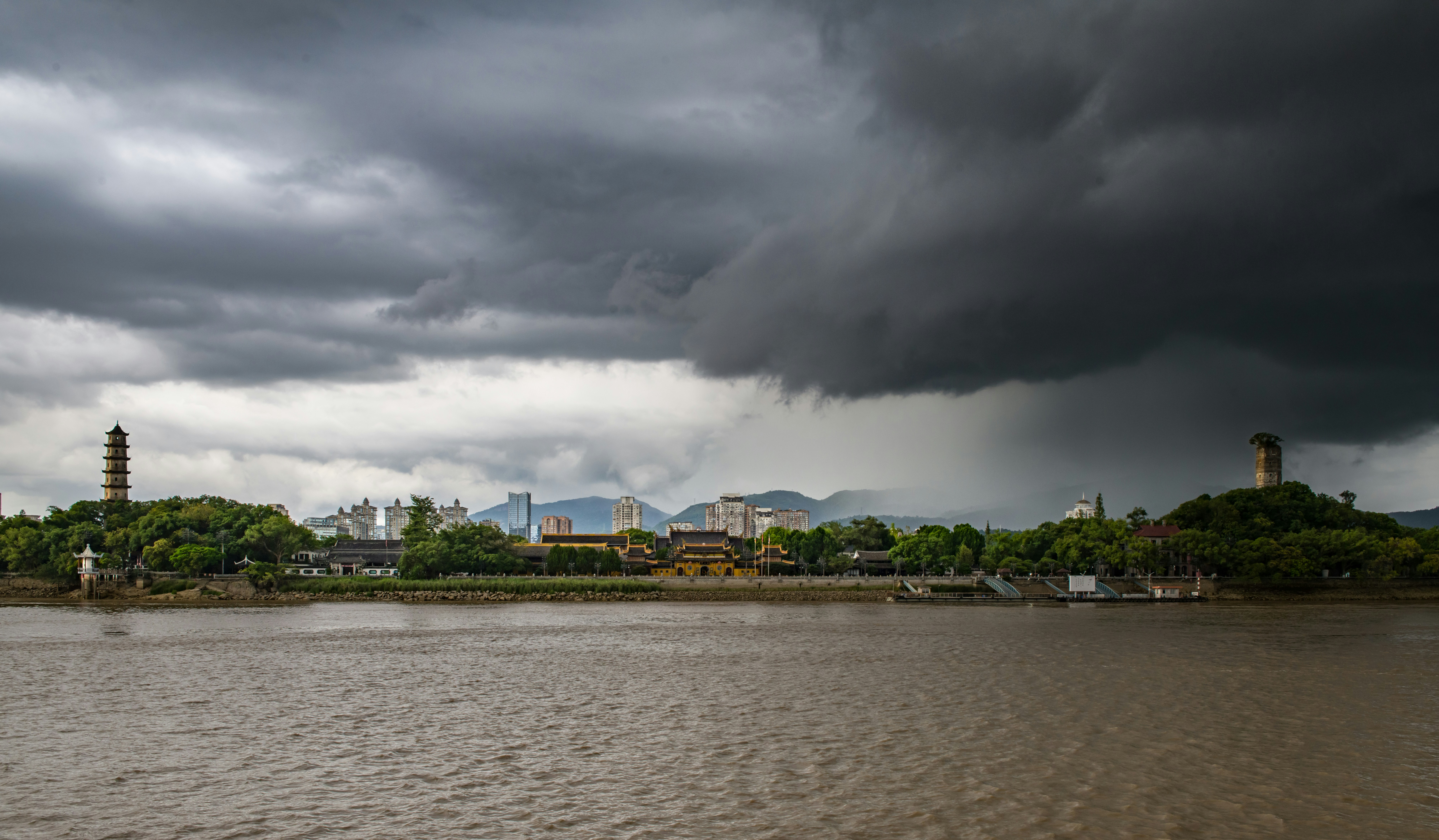 Storm Over the Riverfront: Towers Stand Guard as Clouds Converge