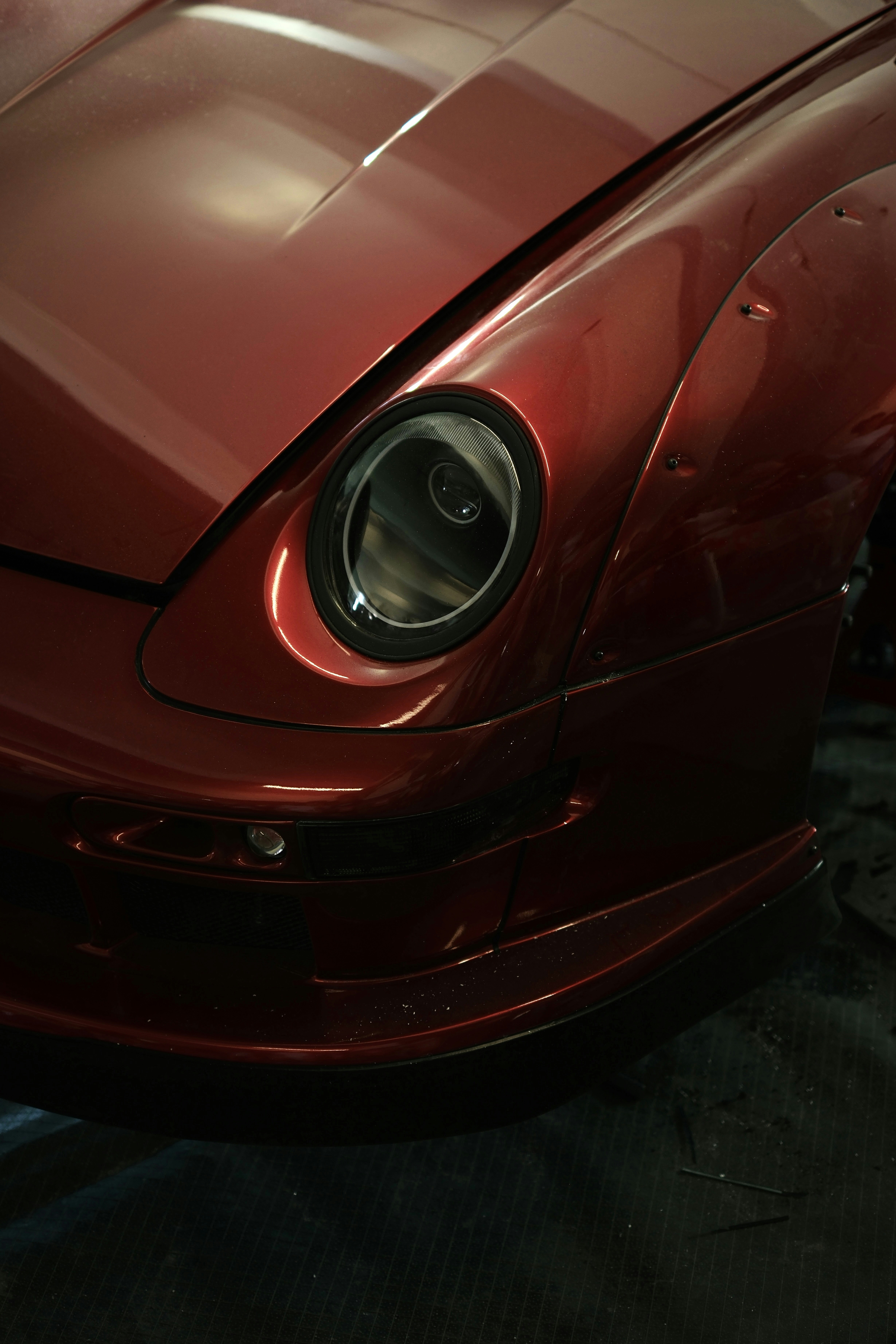 Red Porsche headlamp in a moody garage glow