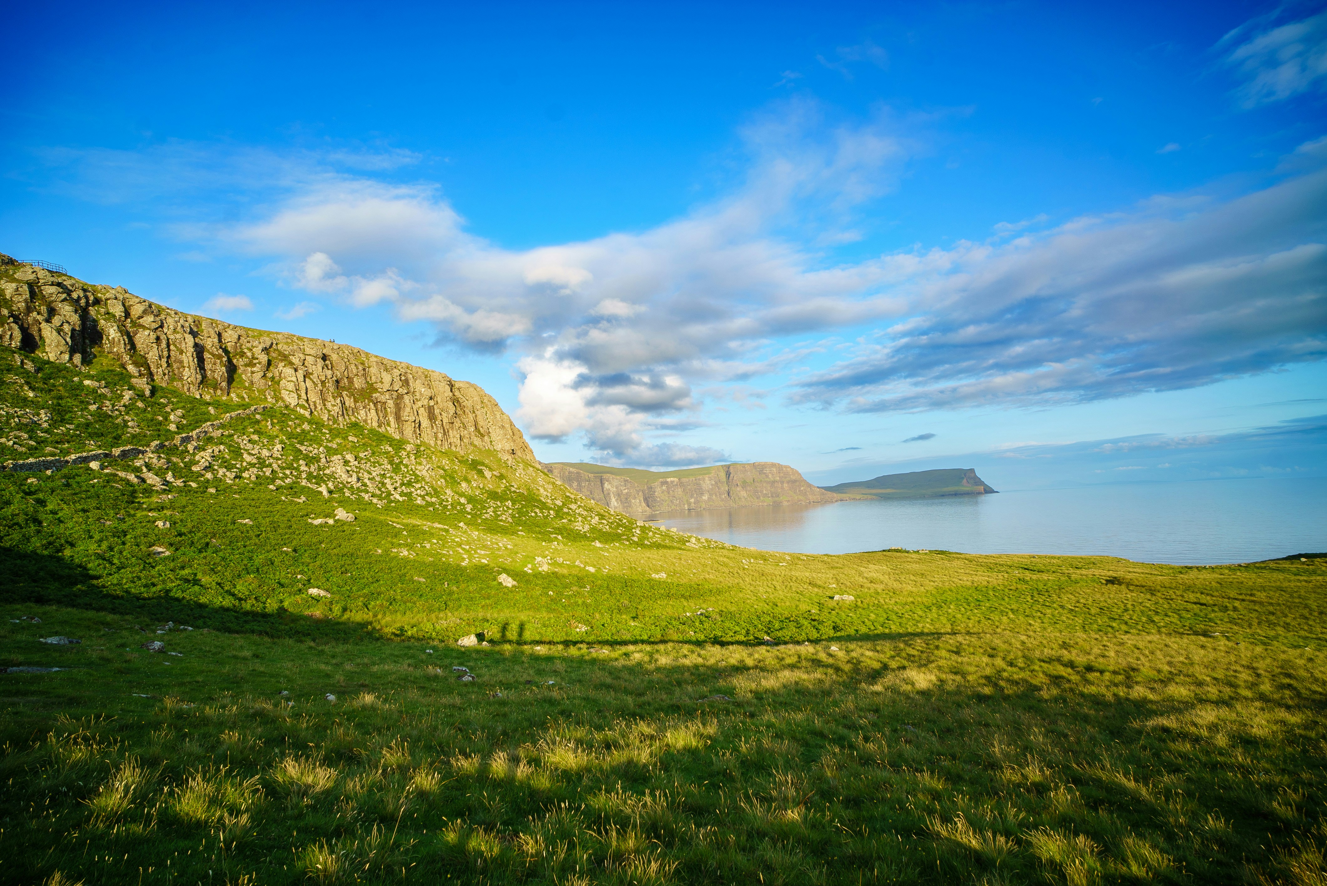 Coastal Cliffs and Open Grassland Under a Wide Blue Sky