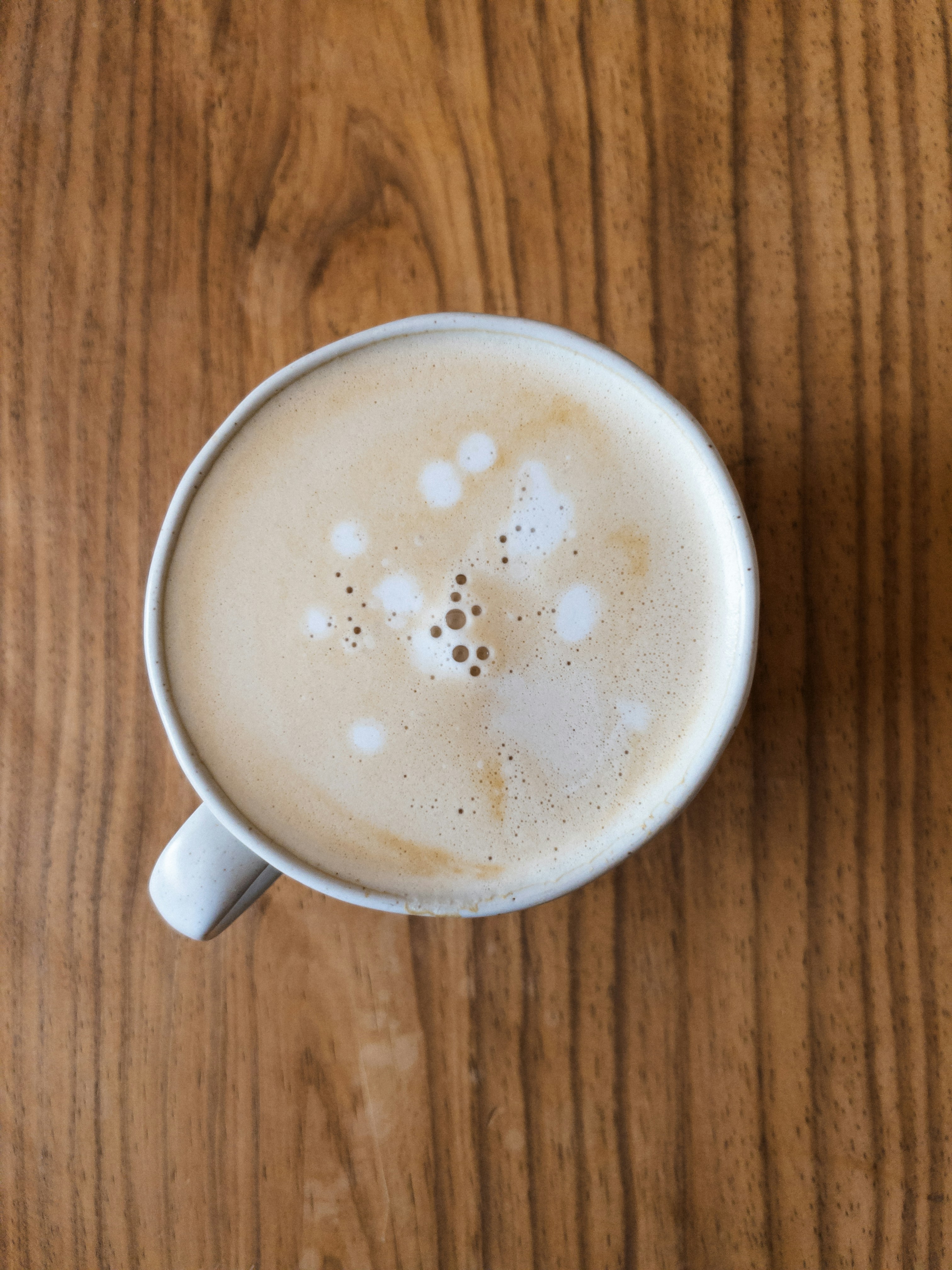 A cup of coffee with foam on a wooden table.