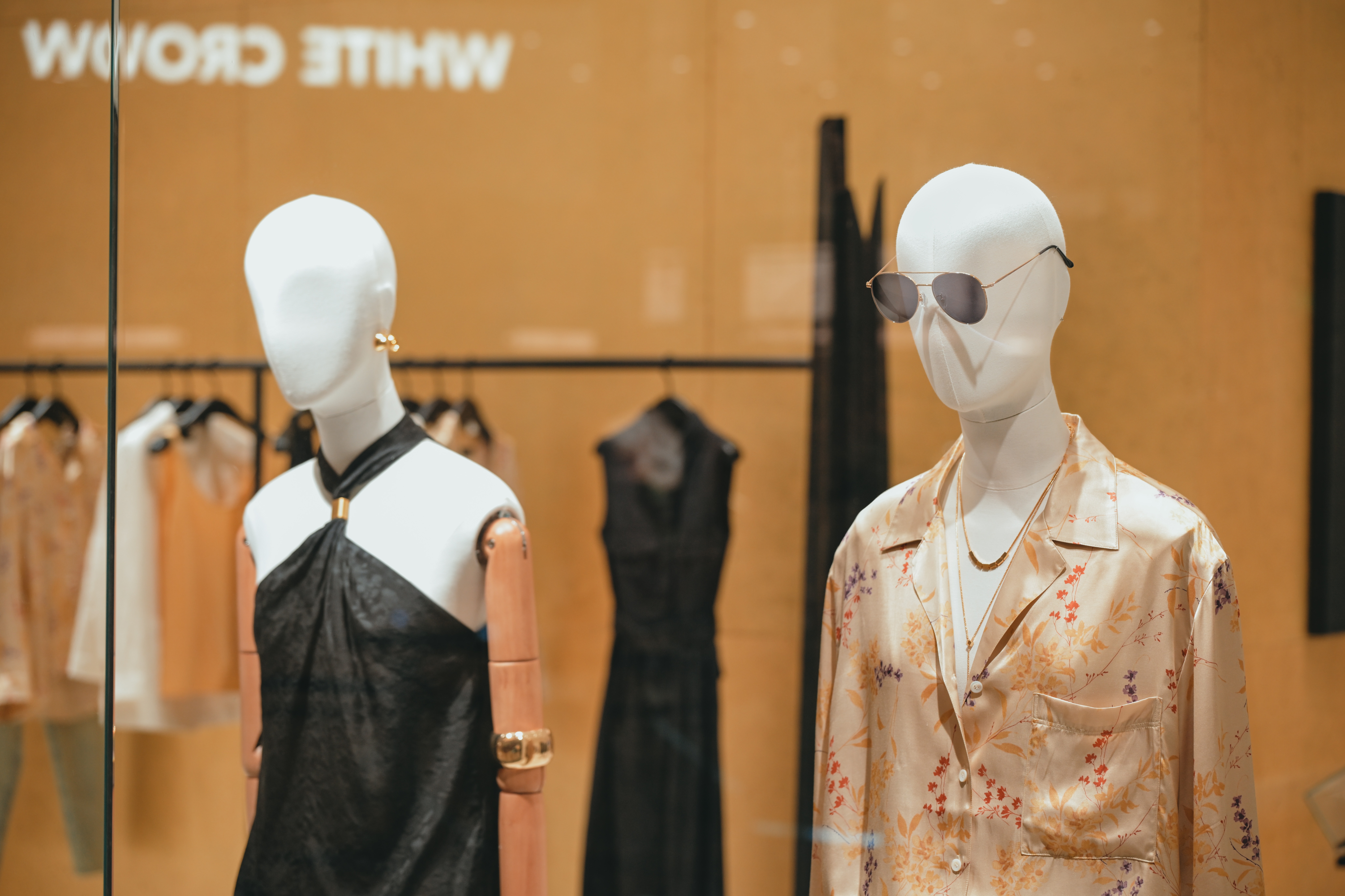 Two mannequins display clothing in a modern store window.