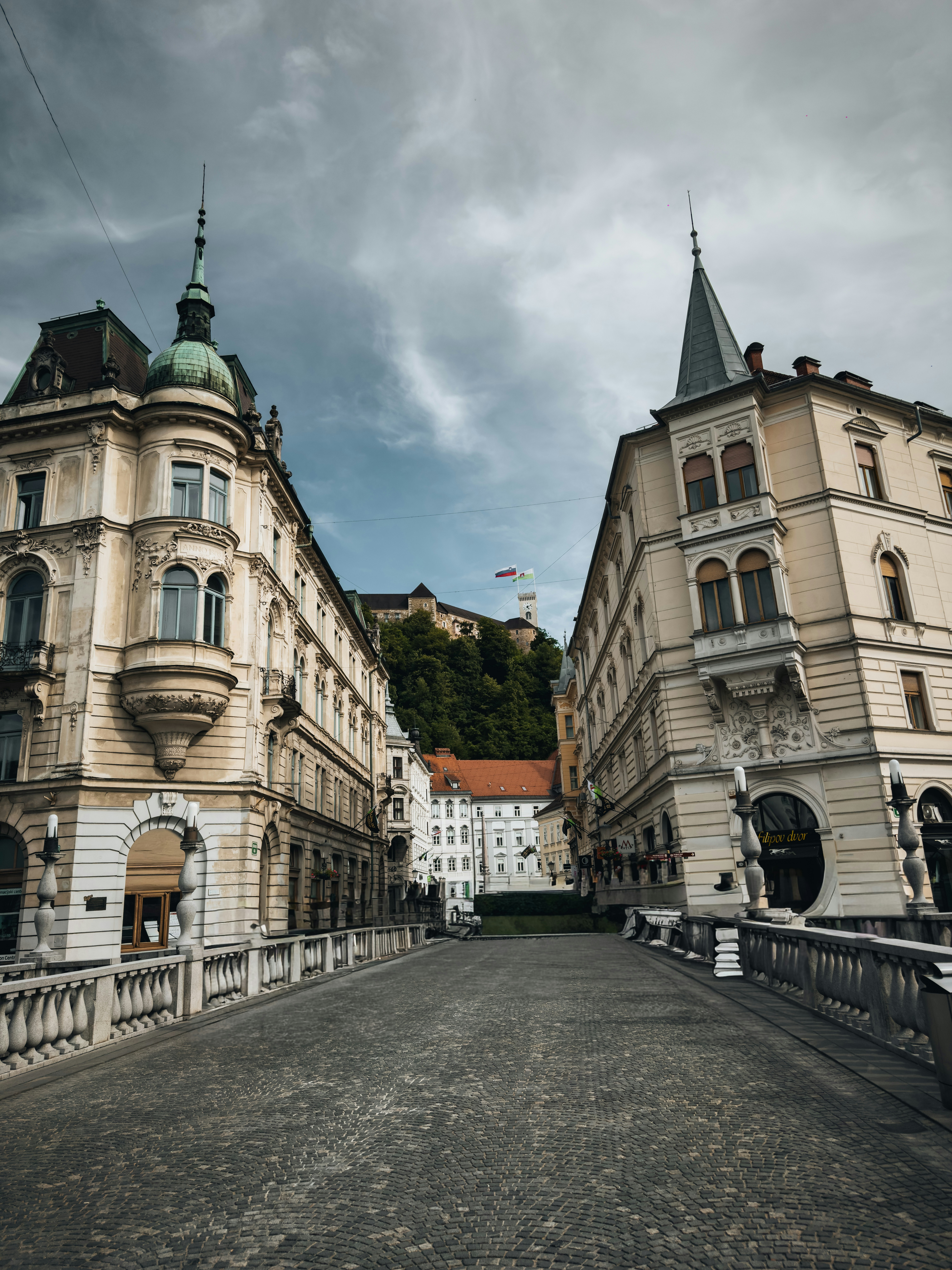 Elegant historic architecture of Ljubljana's old town leading toward Ljubljana Castle in the background. A beautiful European cityscape showcasing Slovenia's capital city and cultural heritage.
