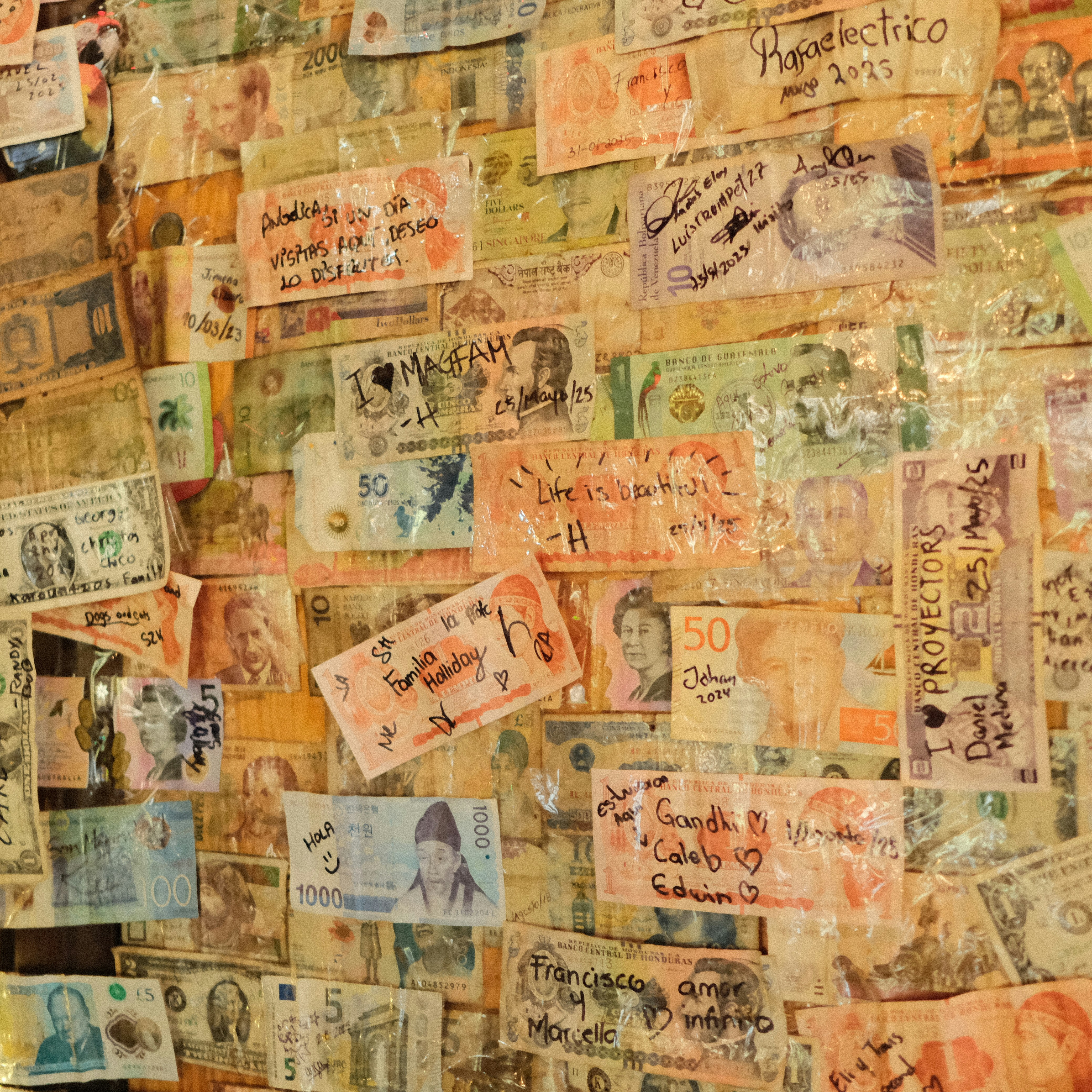 A wall covered with international banknotes and handwritten messages.