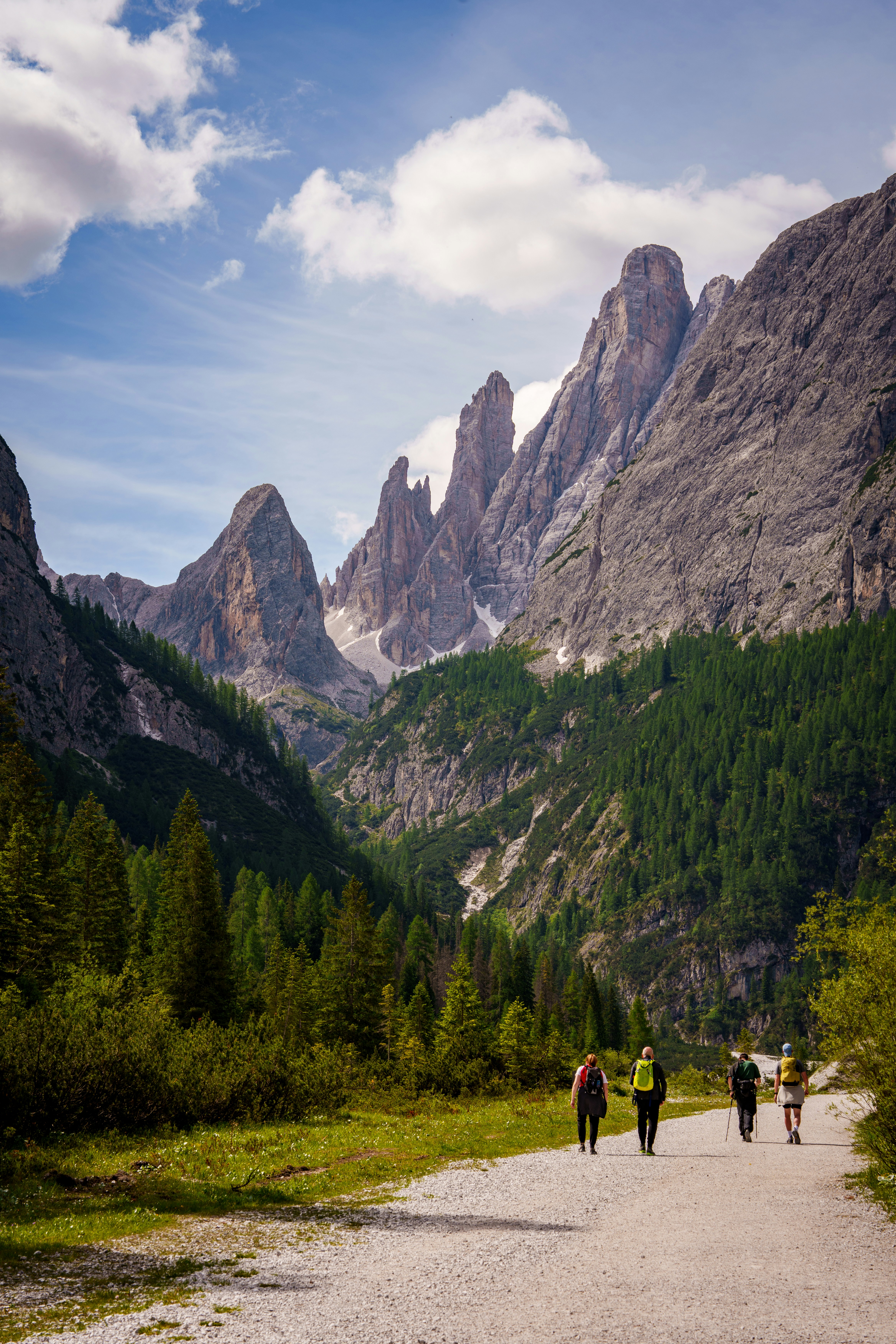 Hikers Beneath jagged peaks along a alpine valley trail