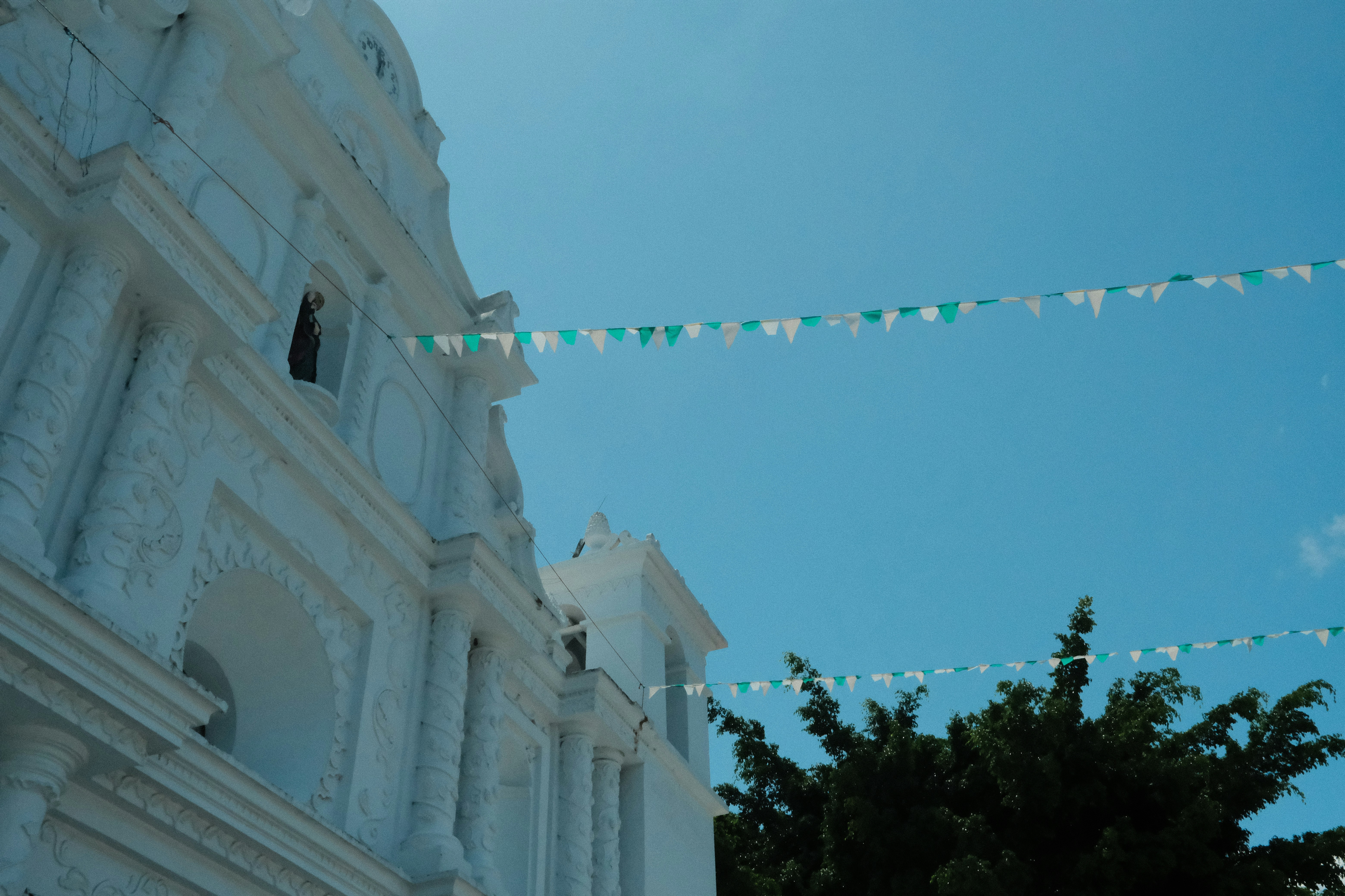 White historic building under clear blue sky with festive banners.