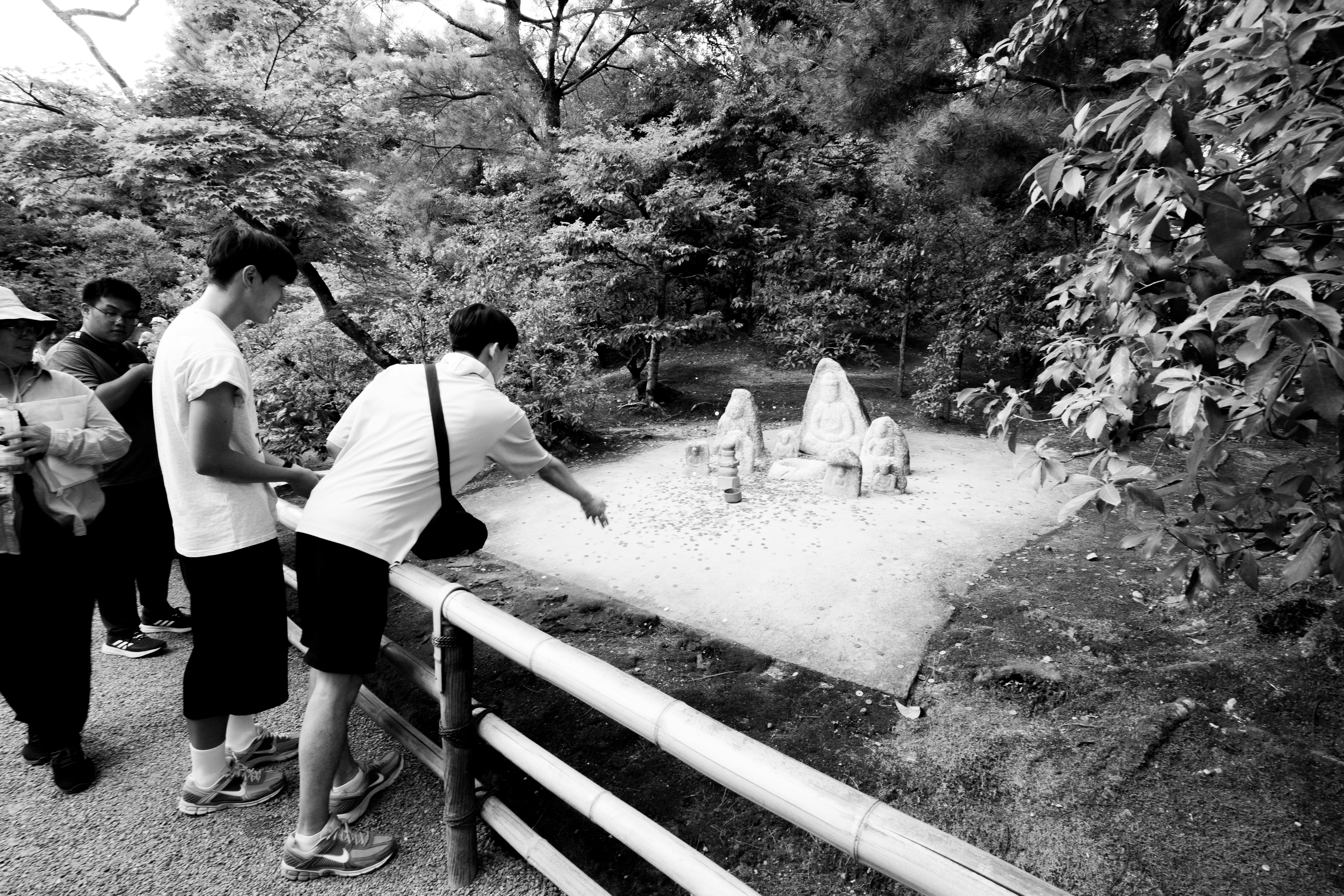 Group of visitors observe a small sand sculpture garden from a railing