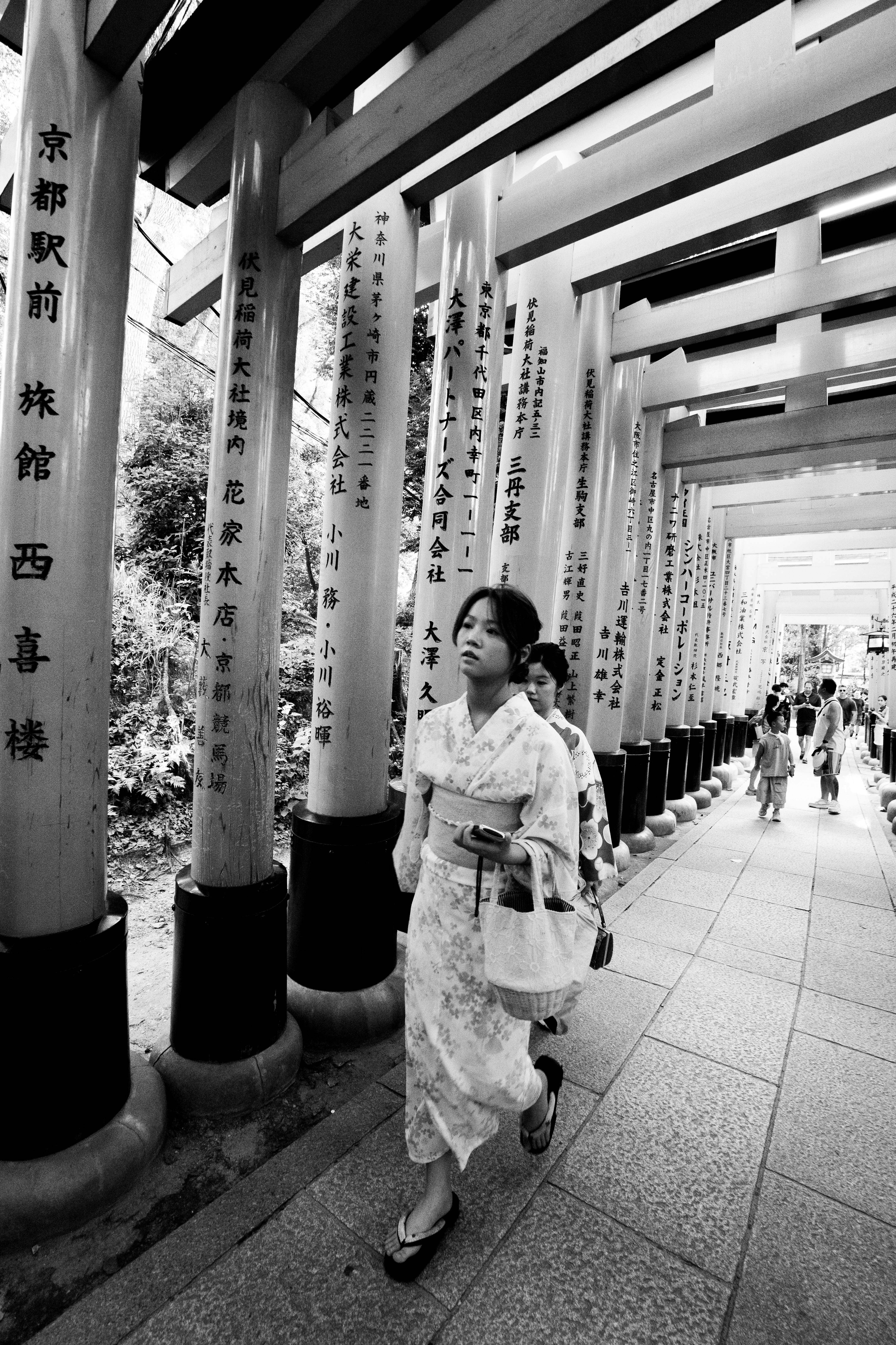 Silent Path Under Slatted Gates: A Woman in White Walks Through a Japanese Torii Gallery