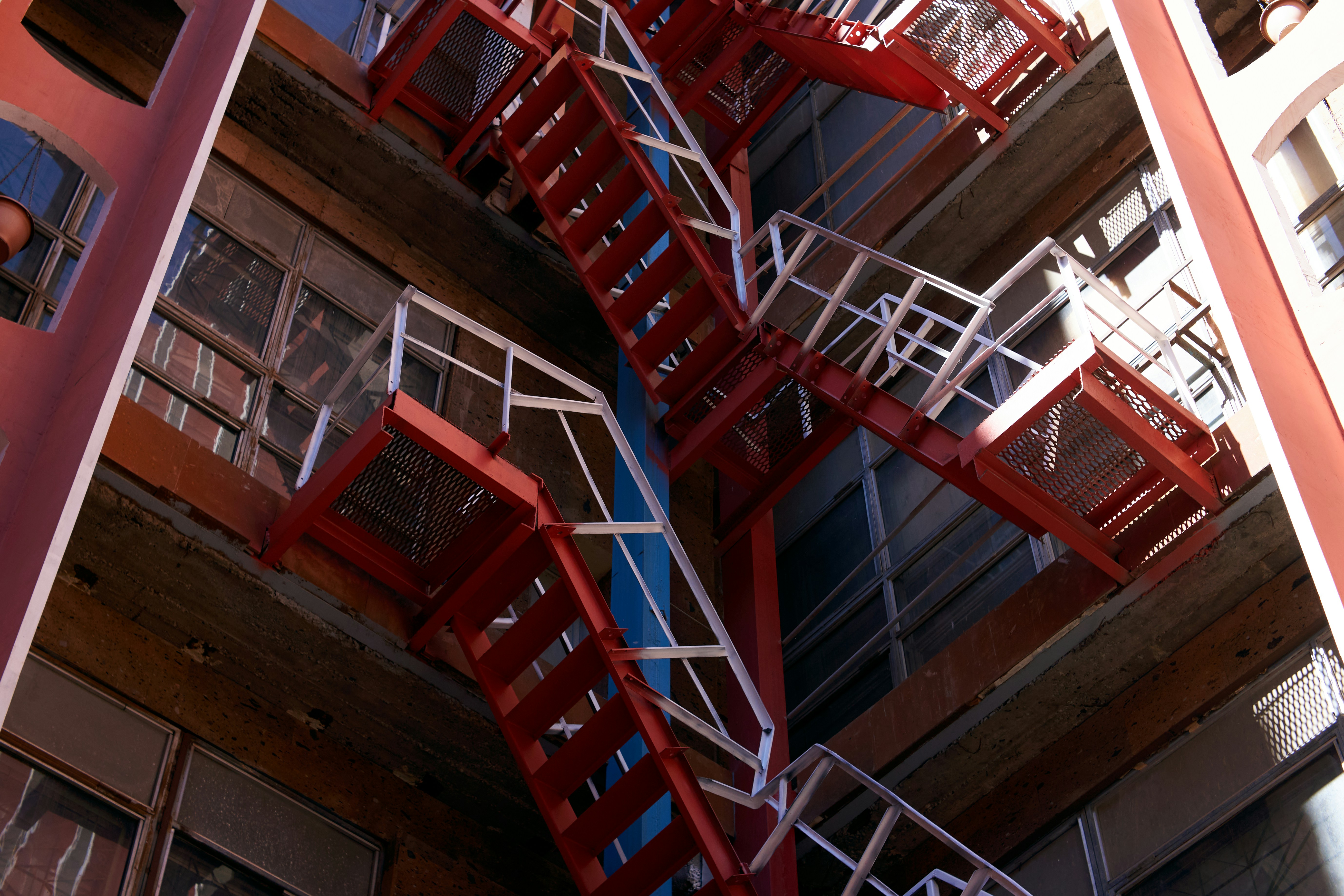 Interwoven Steel: Red Fire Escape Spirals Through Industrial Light