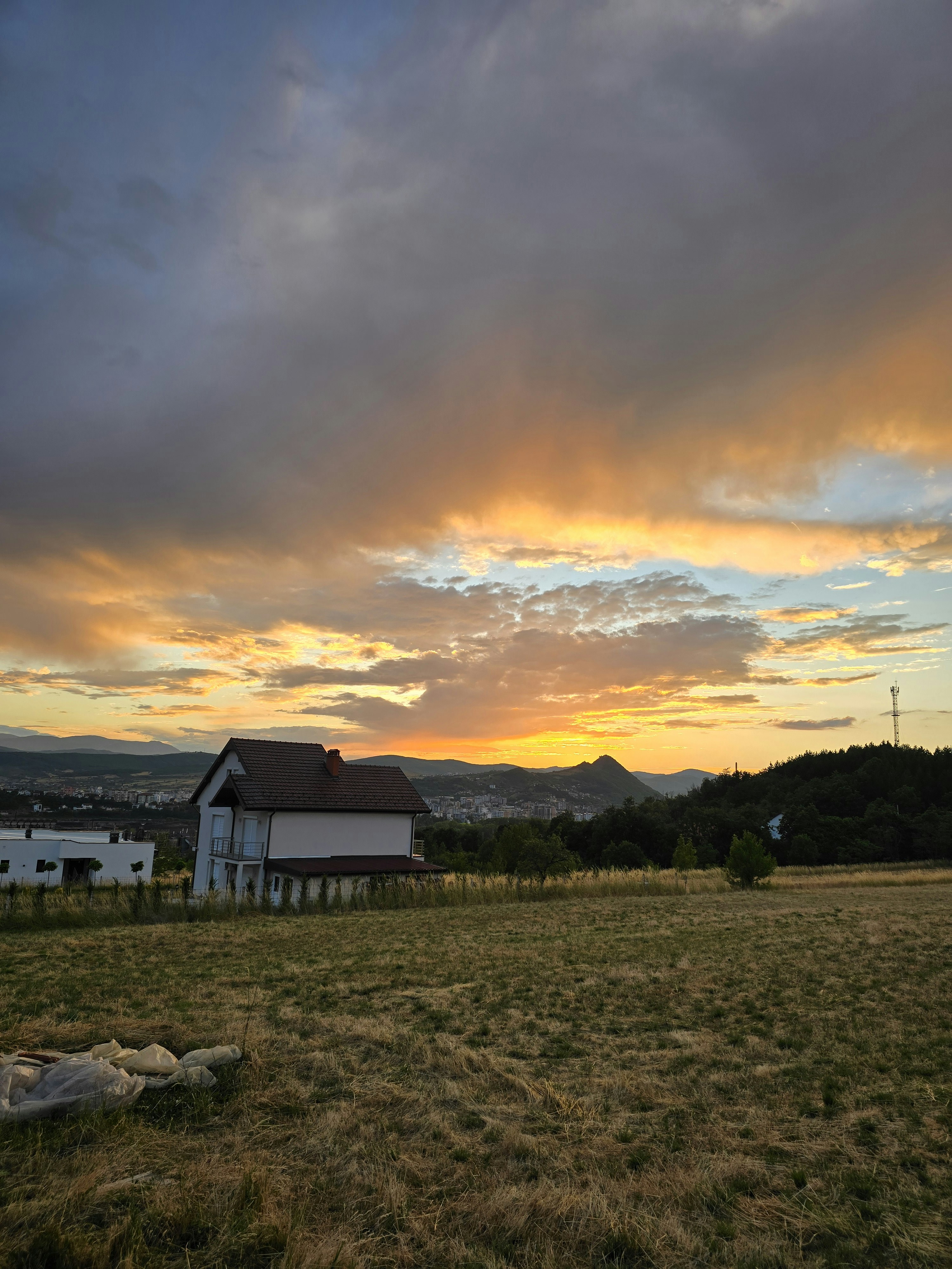 Sunset Over Fields: A Quiet Ridge with a Cottage at Dusk