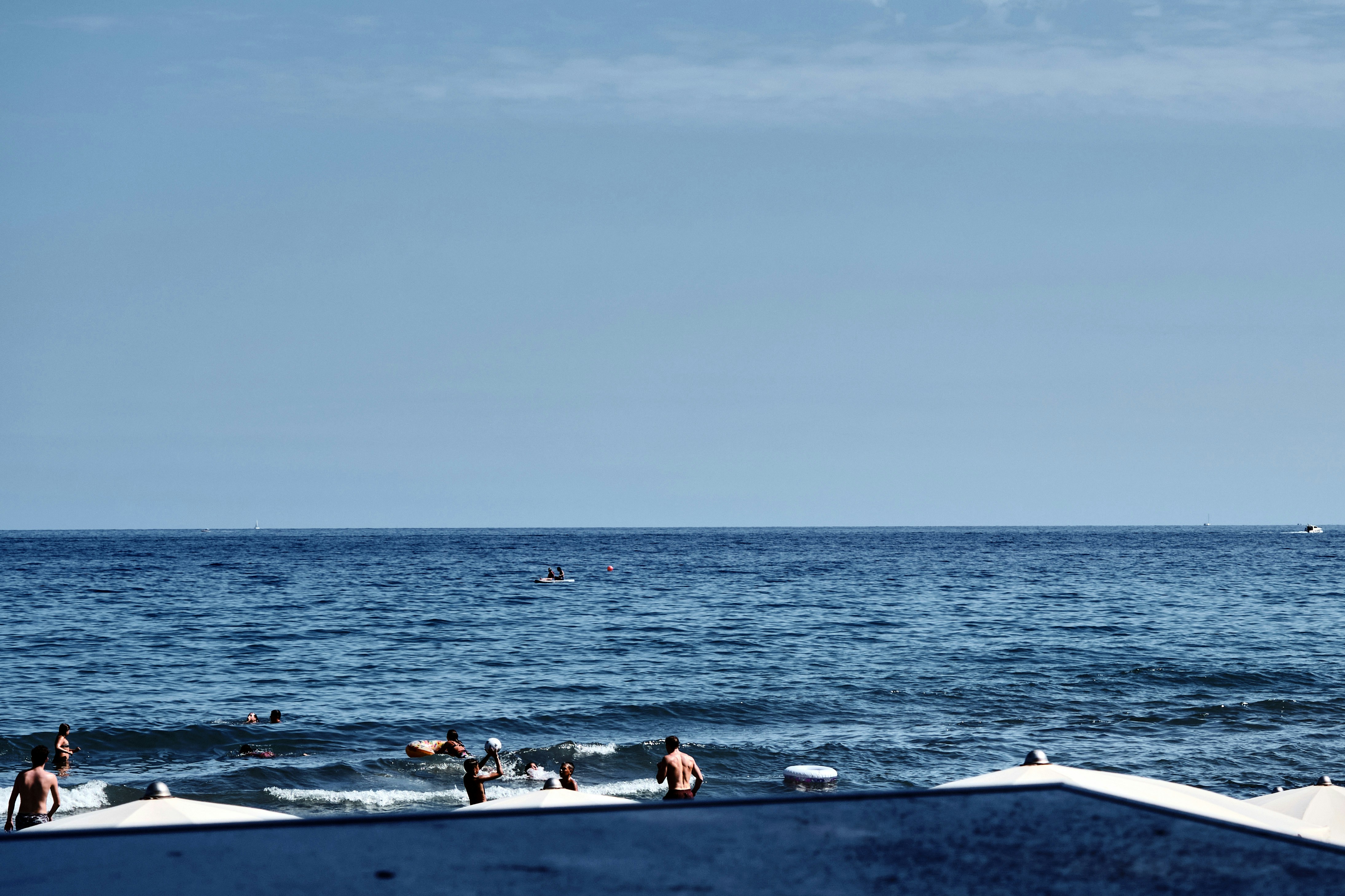 Low-tide Beachfront, Boats and Distant Swimmers on a Calm Sea