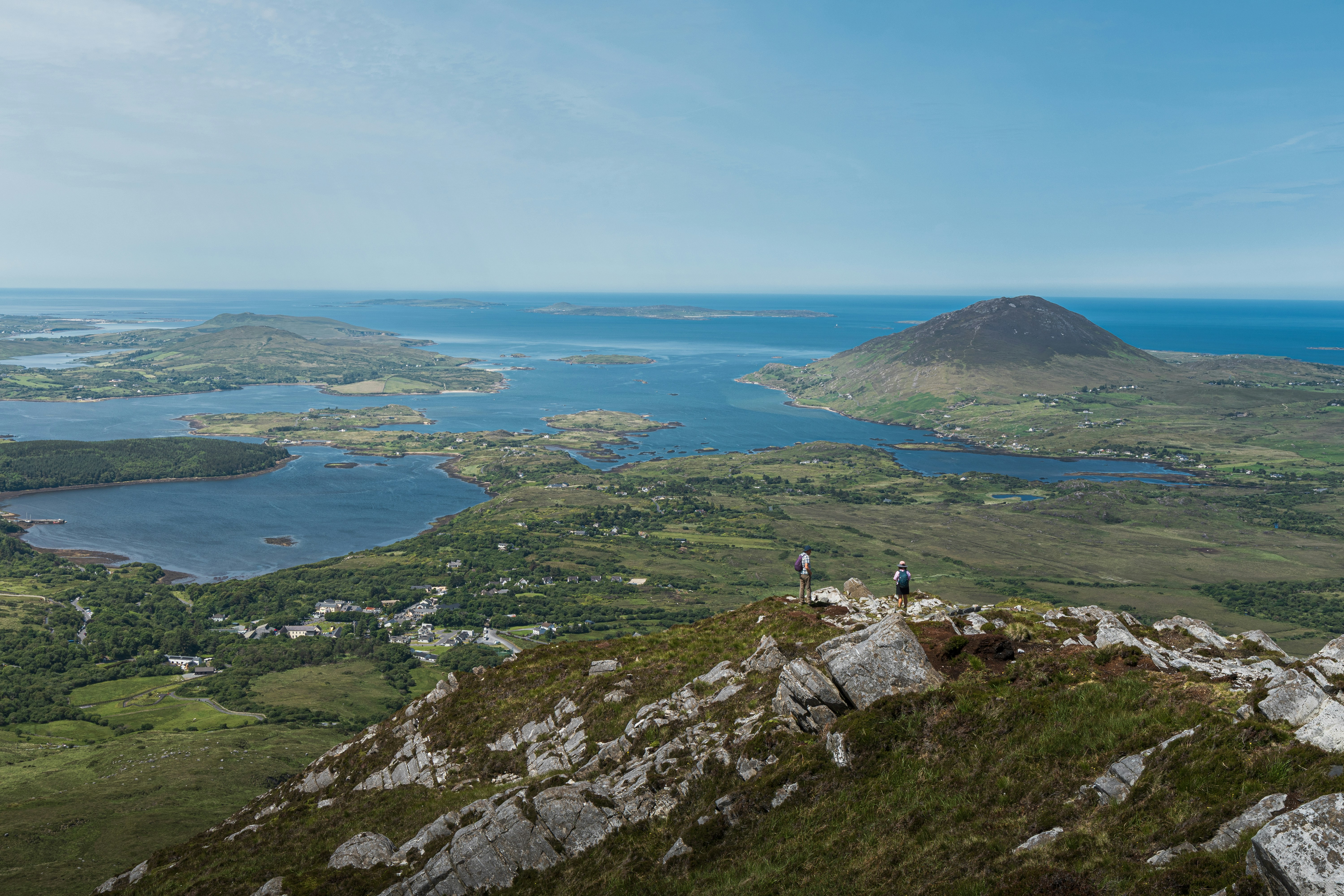 Hikers atop a windswept ridge overlooking a mosaic of lakes and islands