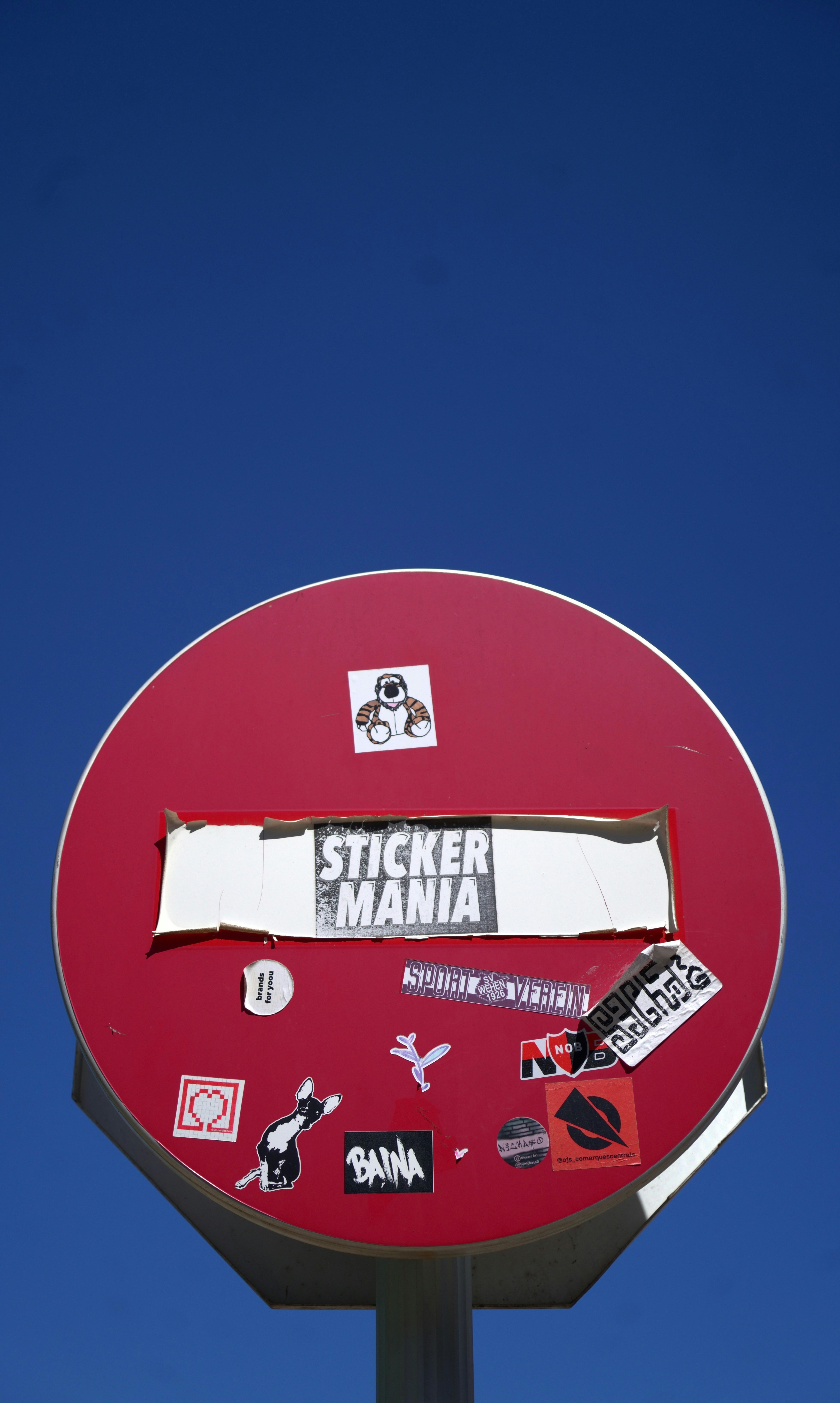 Sticker Storm on a Red Circular Sign Against a Cerulean Sky
