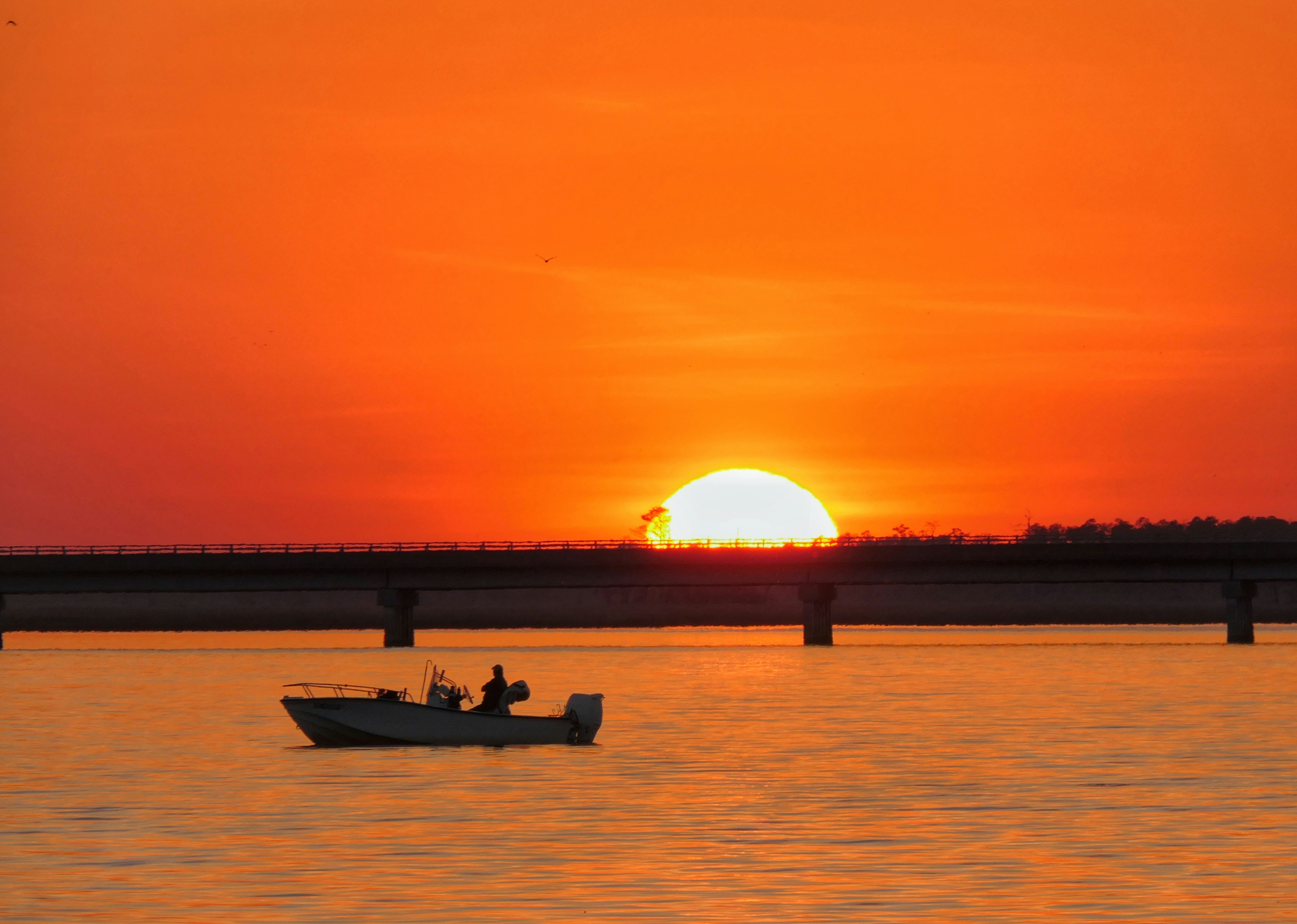 Golden Hour Drift: Boat Silhouette Against a Rising Sun