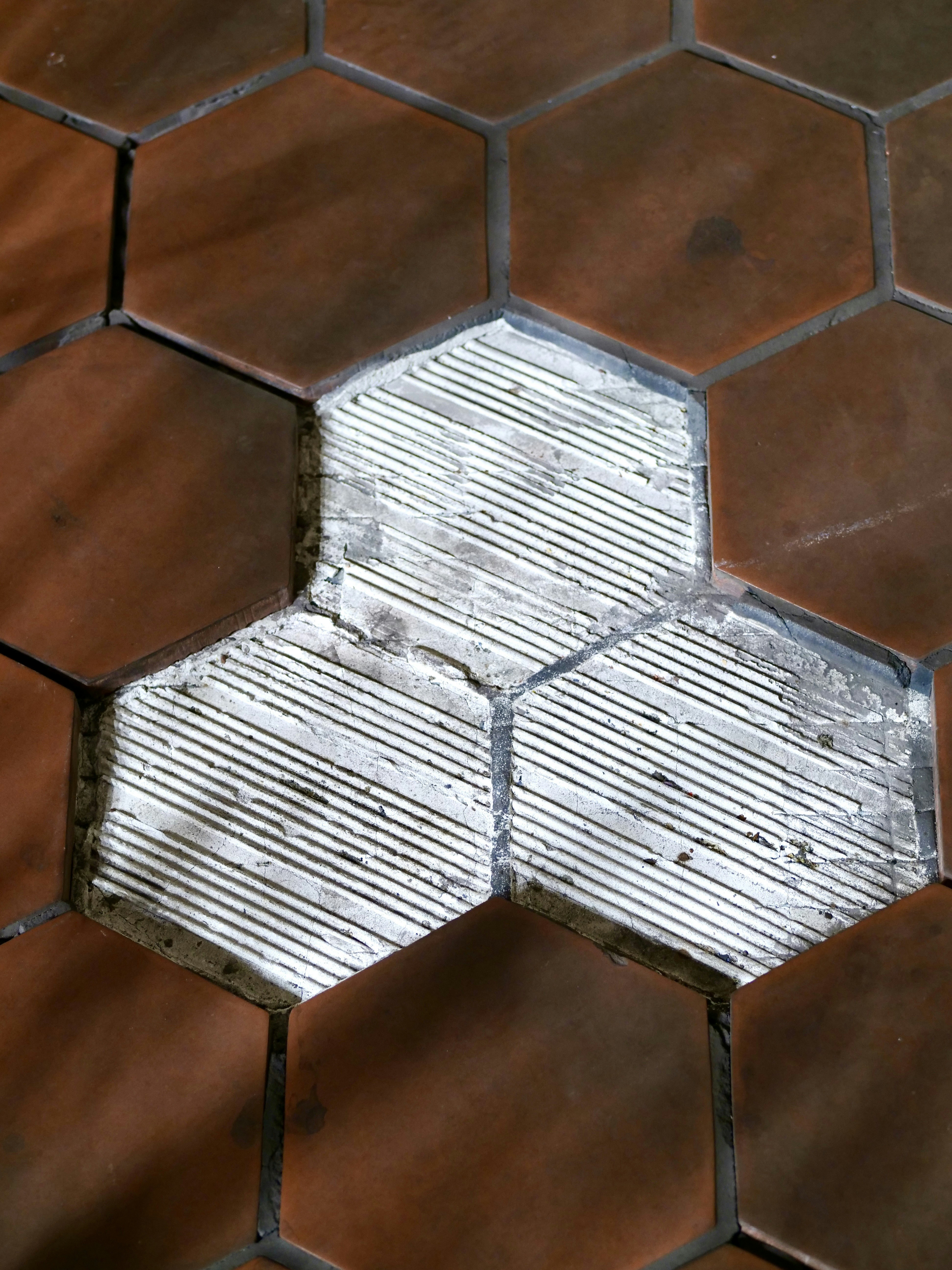 Three White Striped Tiles Amidst Brown Hex Tile Mosaic