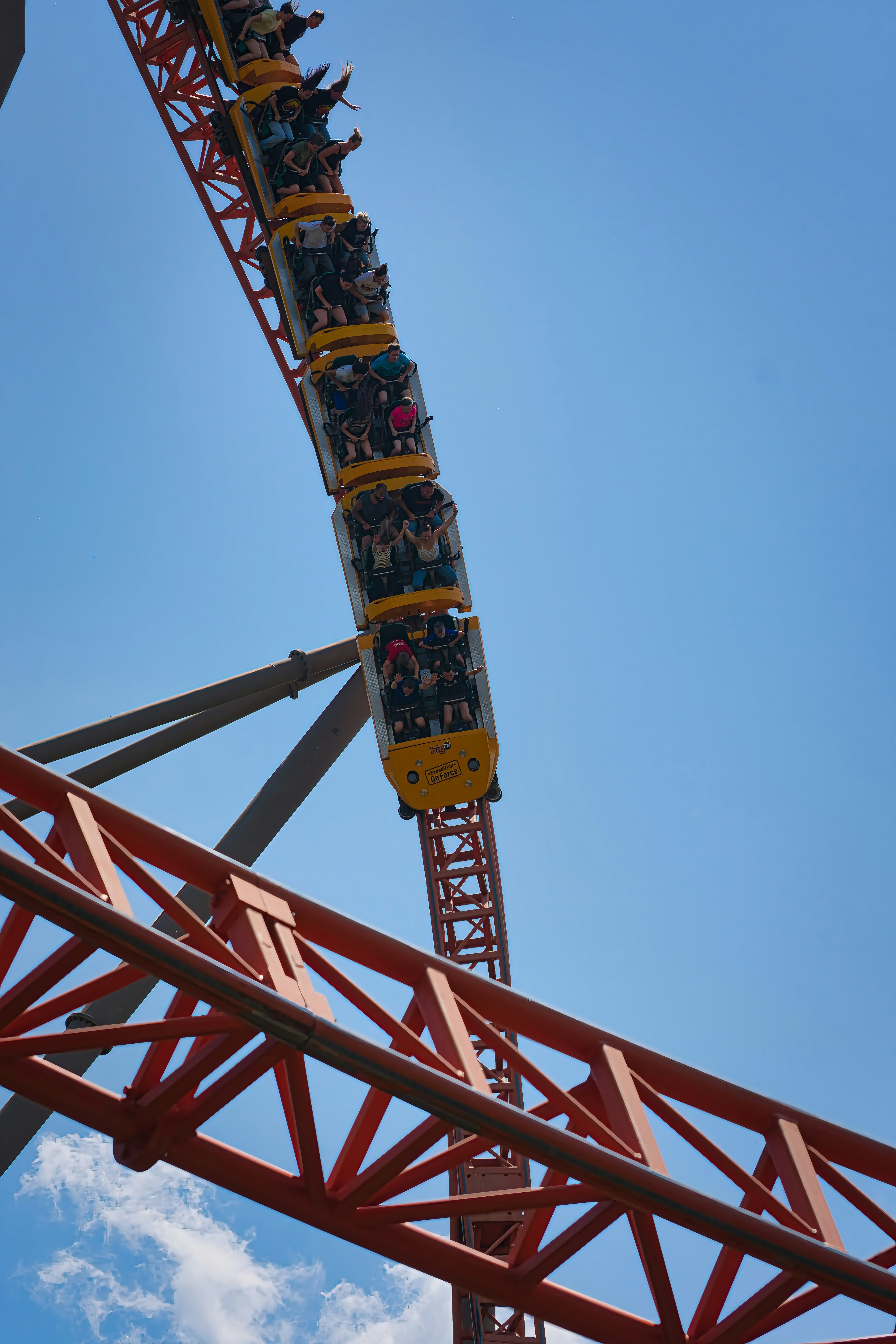 Curve of Courage: Riders Surging along a Roller Coaster Amid a Crisp Blue Sky