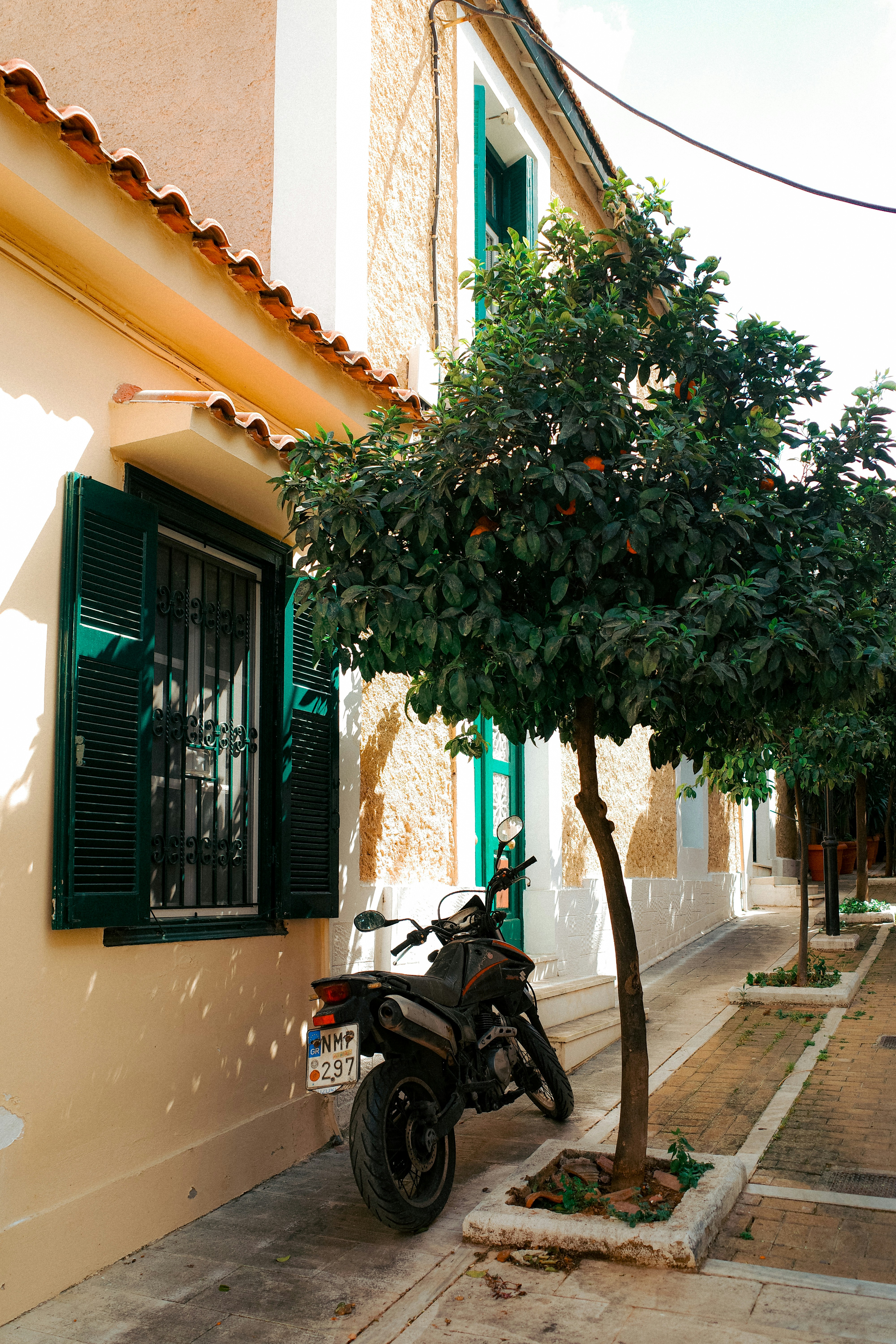 Sunlit Mediterranean Street with Orange Tree and Scooter