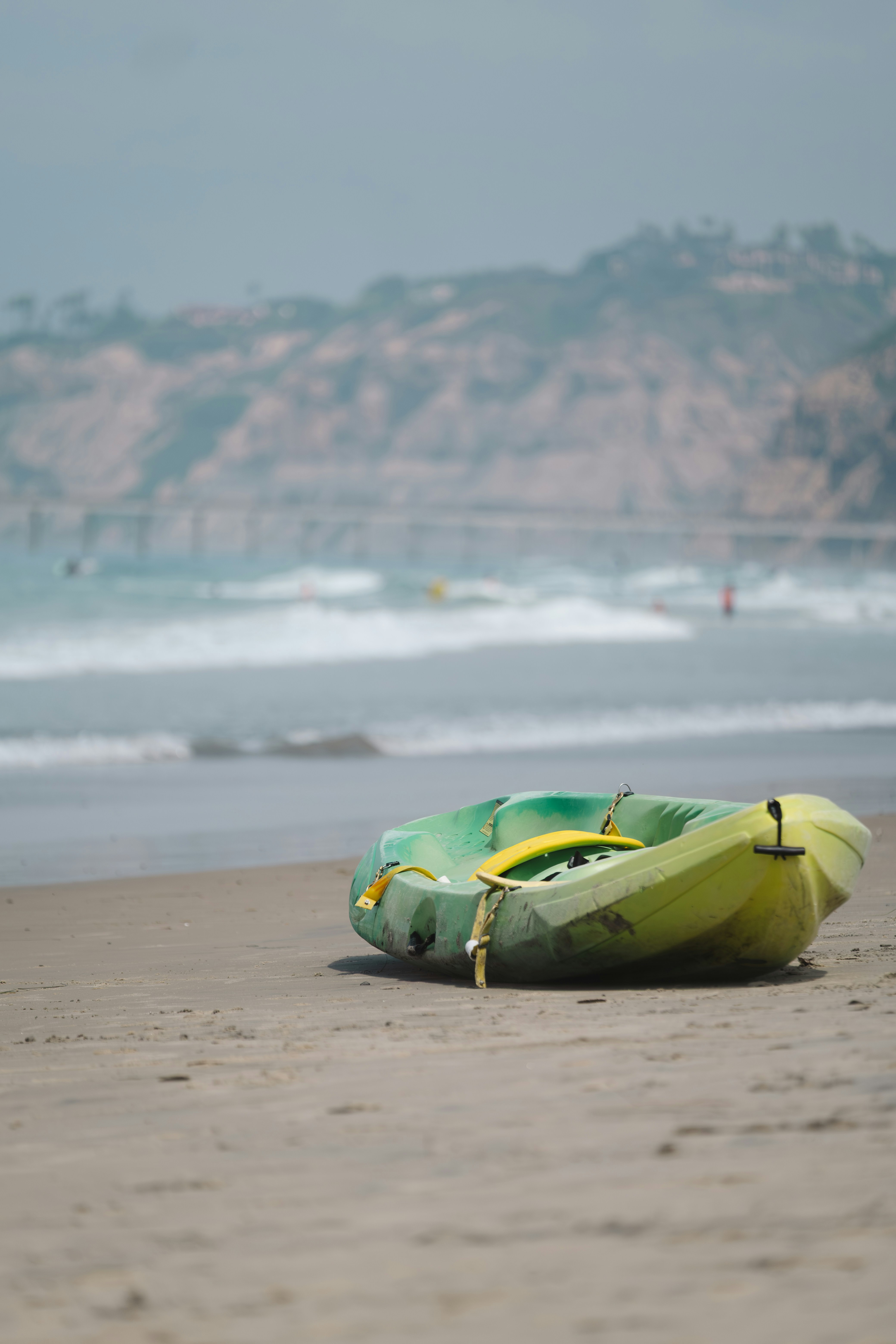 Green Boat Resting on Quiet Shore Beneath a Distant Surf