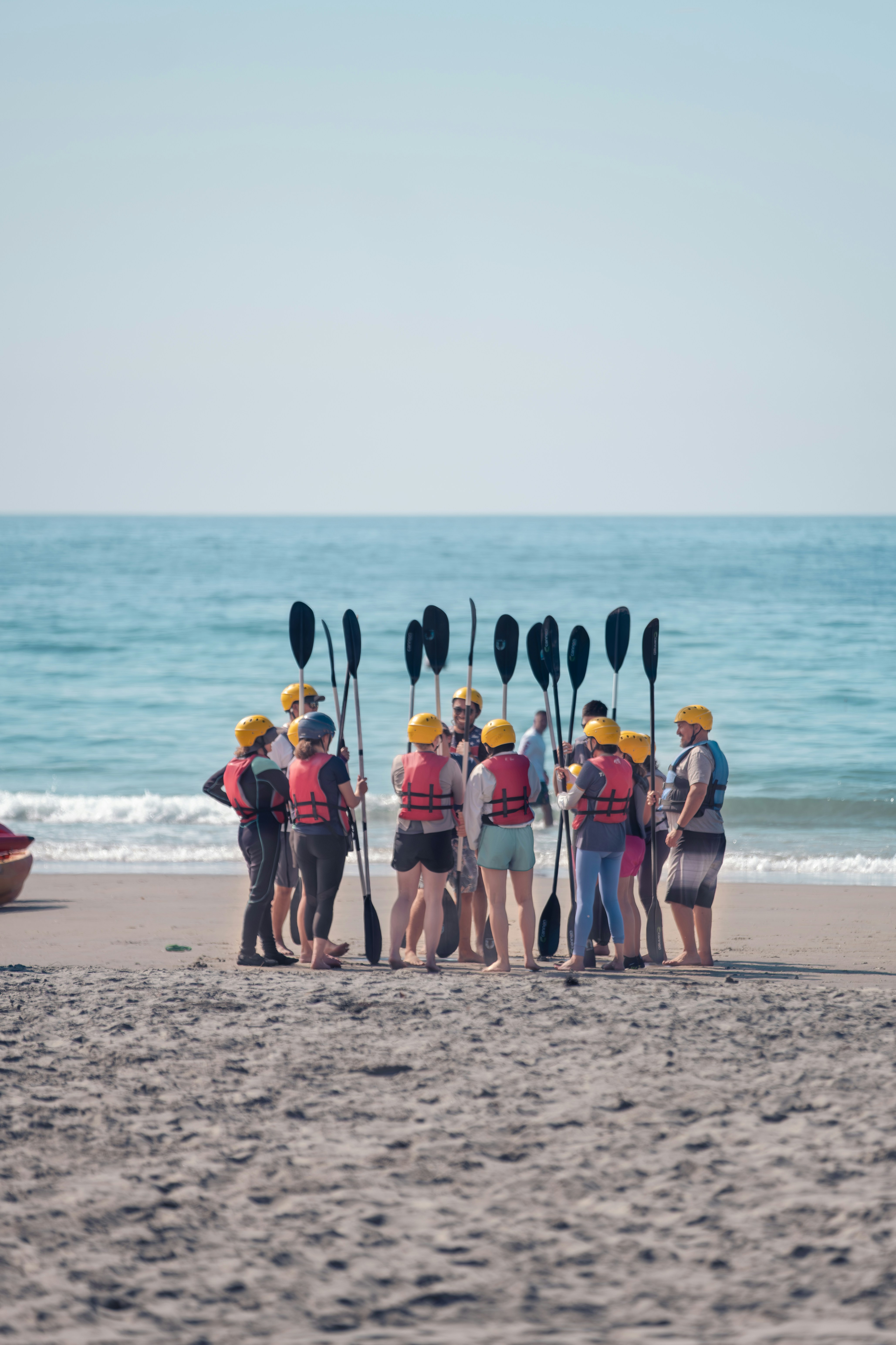 Crew Huddle on the Shore: Paddles Raised in Unison