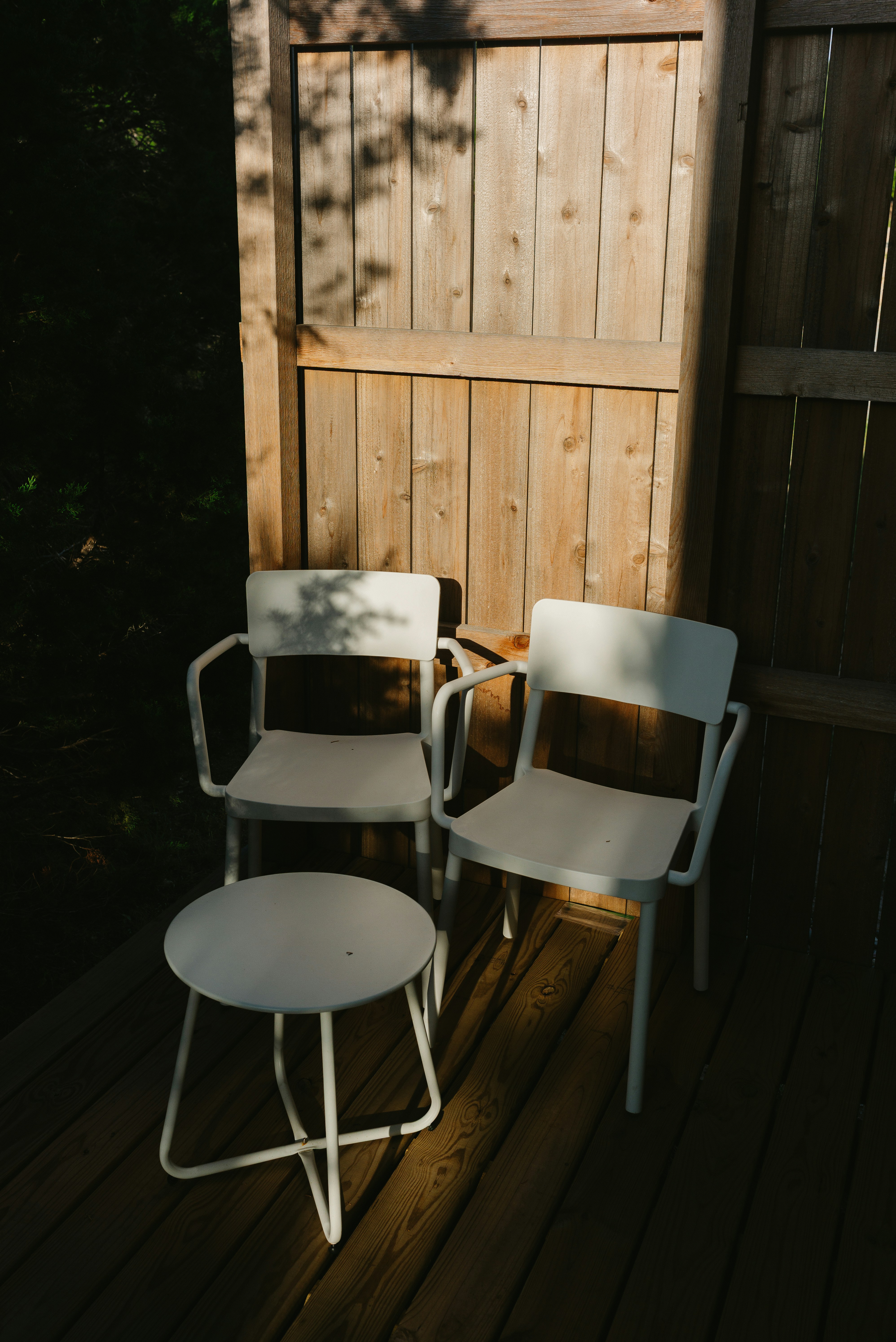 Sunlit Terrace: White Chairs in a Quiet Backyard